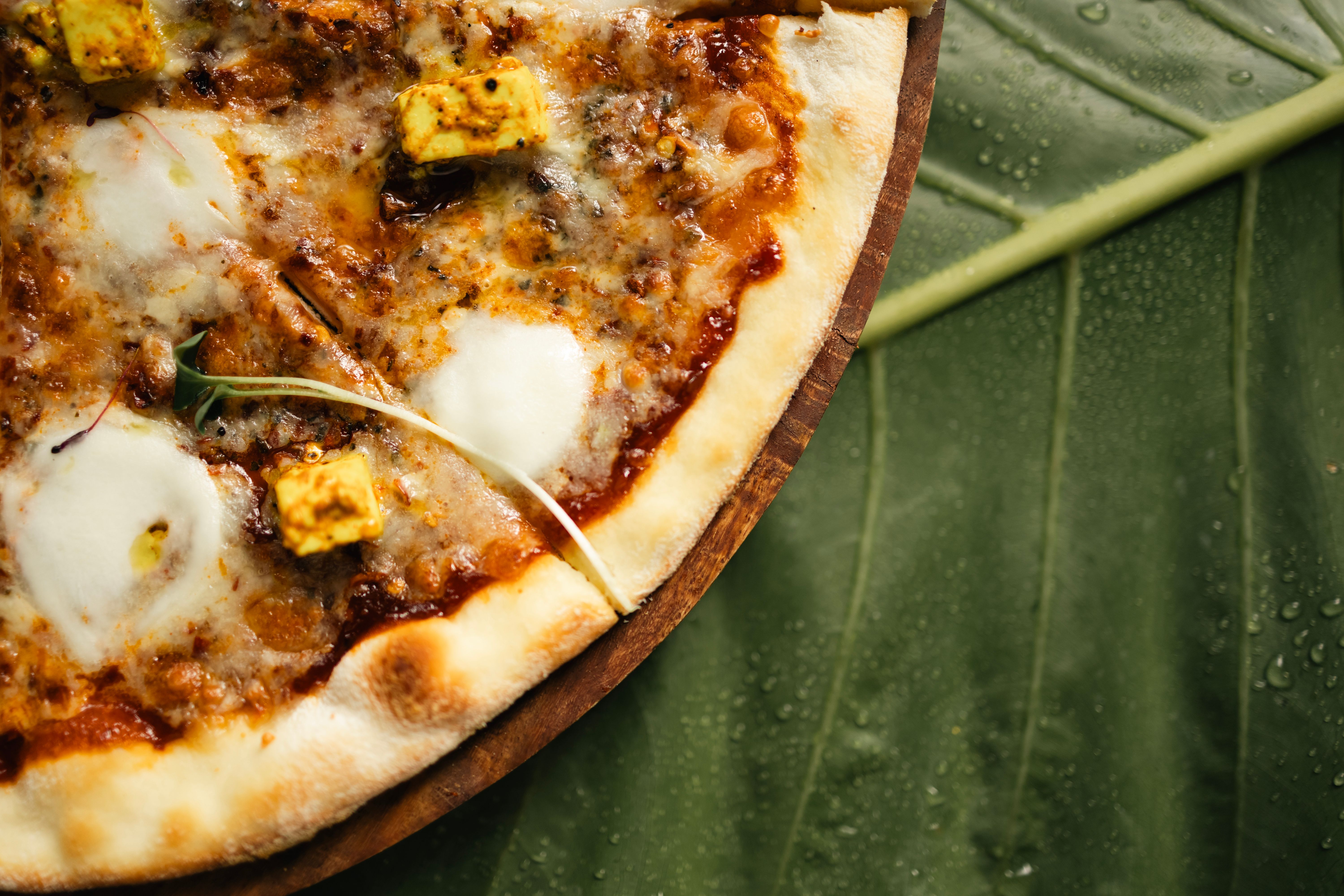 Delicious Paneer Pizza on Green Leaf Background · Free Stock Photo