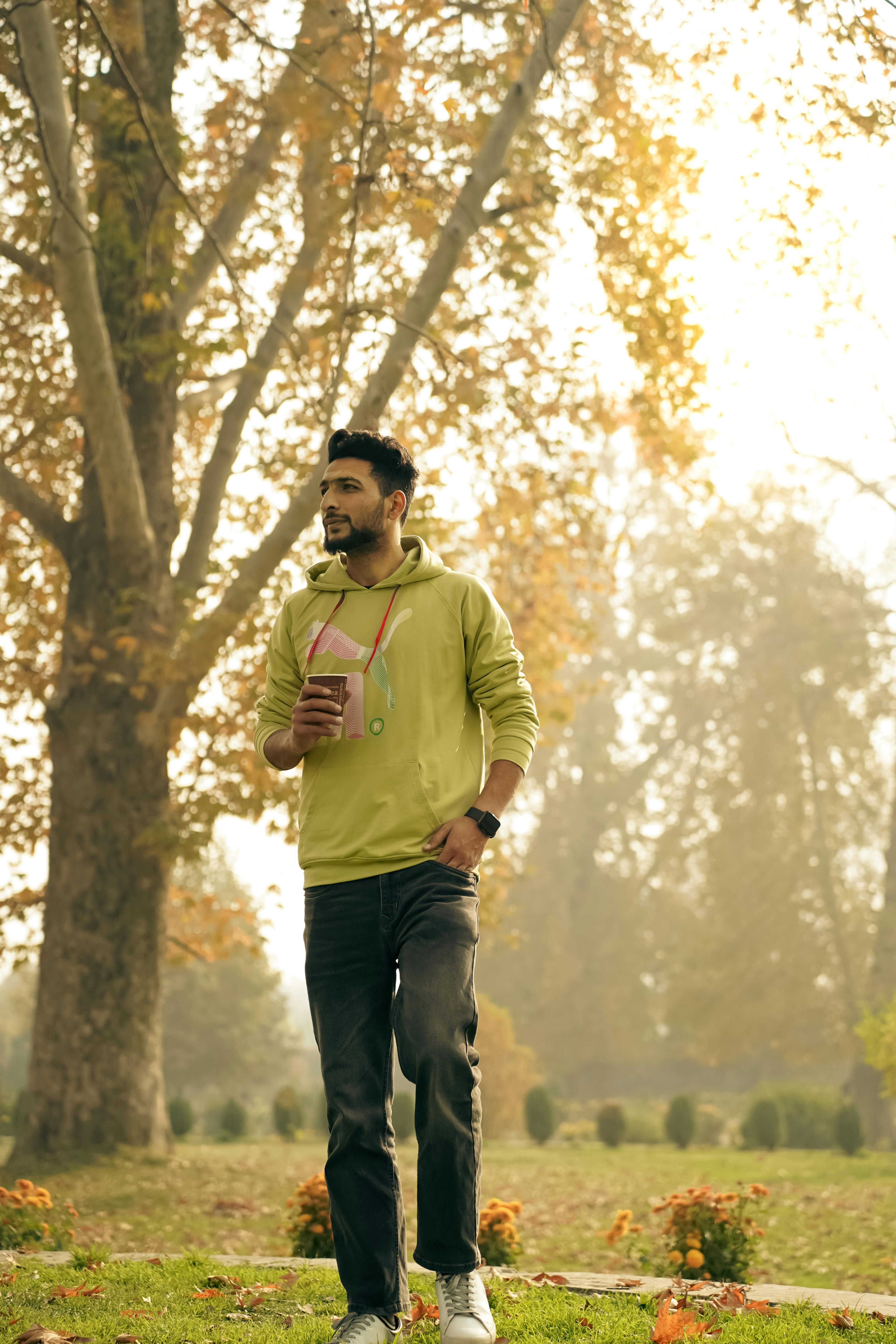 Man Walking in a Park with a Coffee in his Hand · Free Stock Photo
