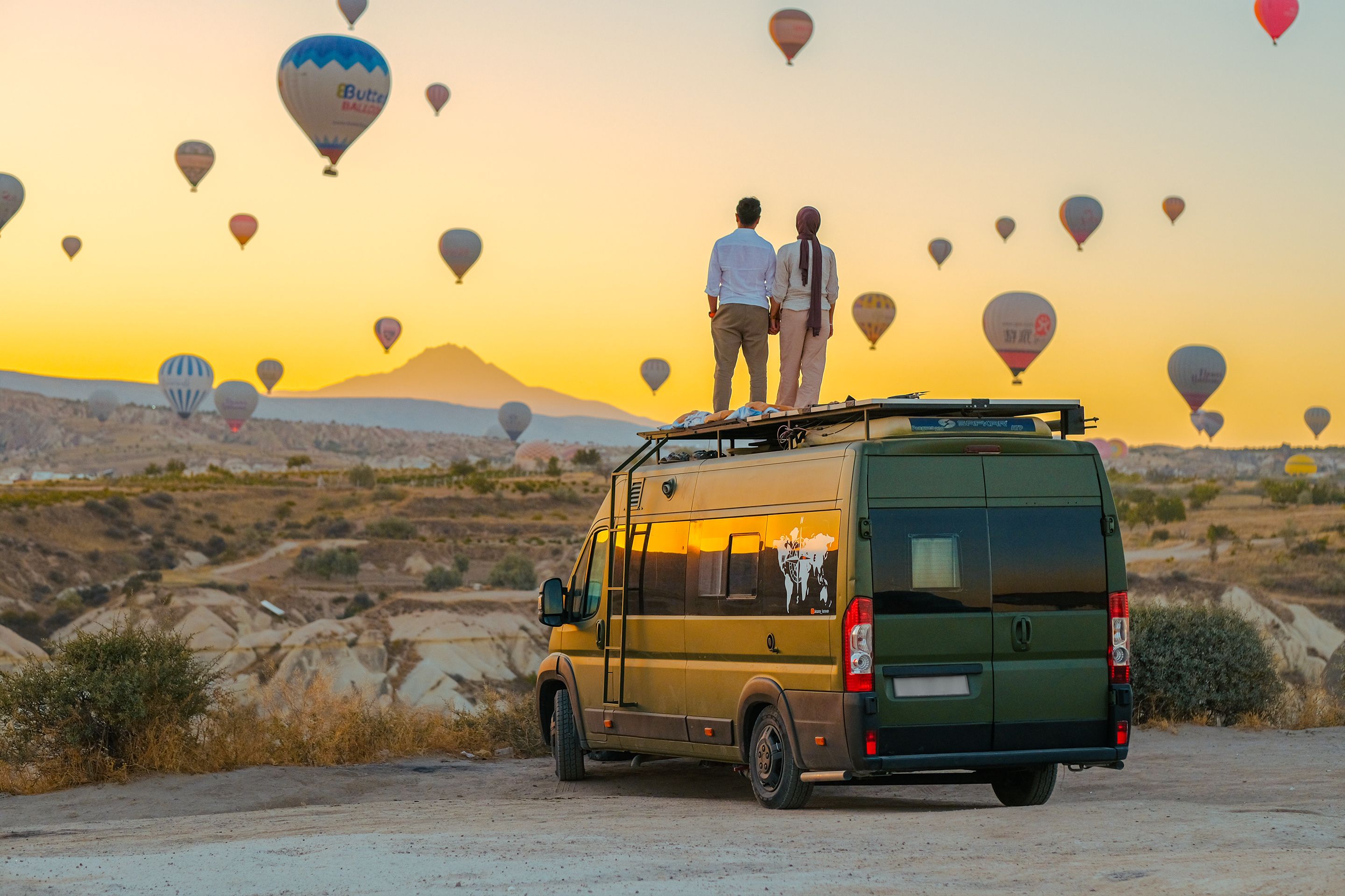 Hot-Air Balloons in the Yellow Sky over a Desert, and People Standing ...