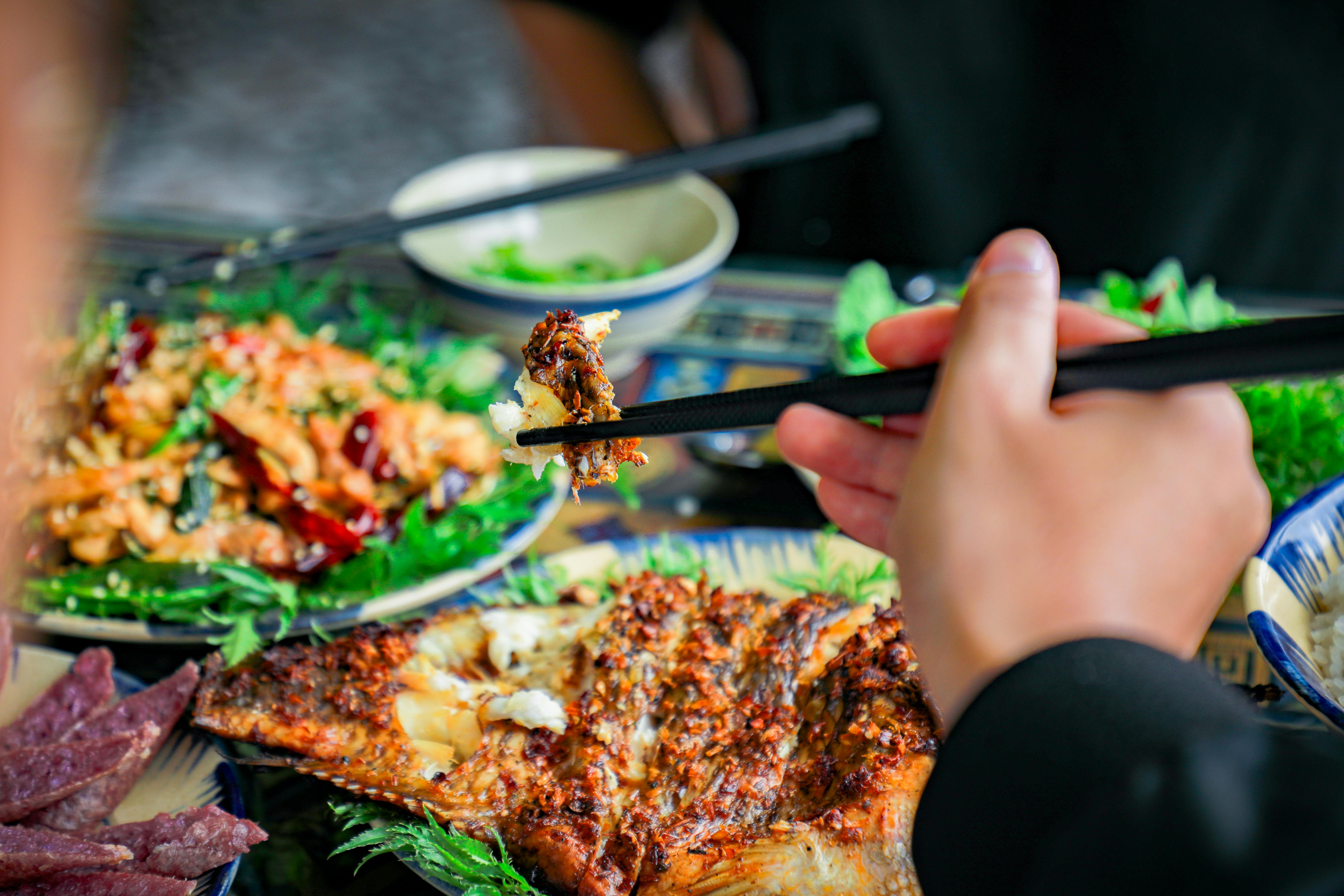 Close-up of a Person Grabbing Food from the Table with Chopsticks ...