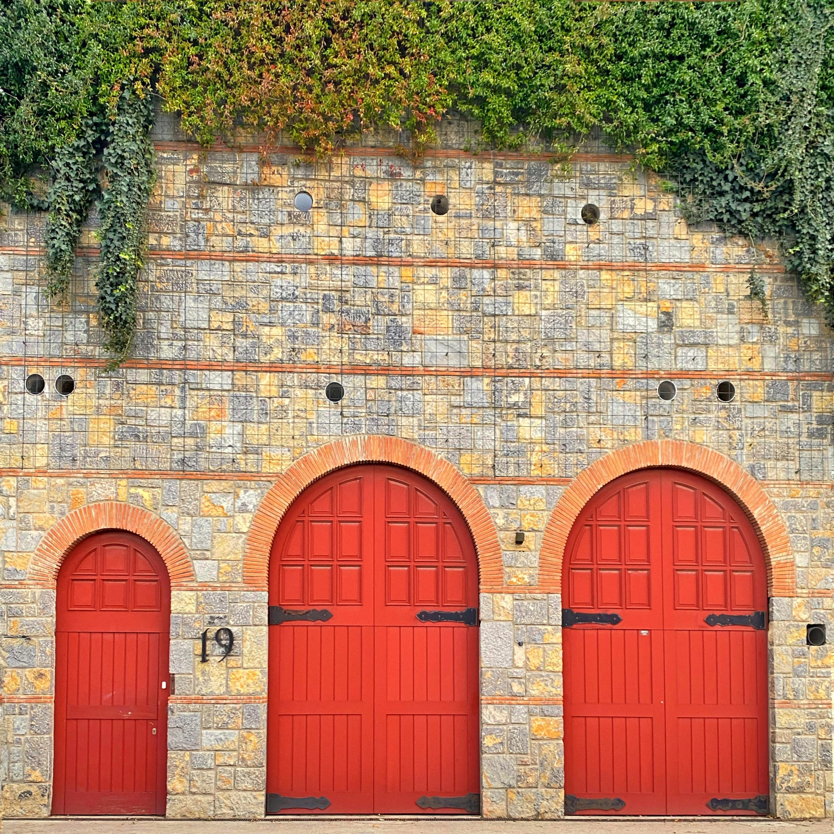 Red Arched Doors in a Stone Wall with Ivy · Free Stock Photo