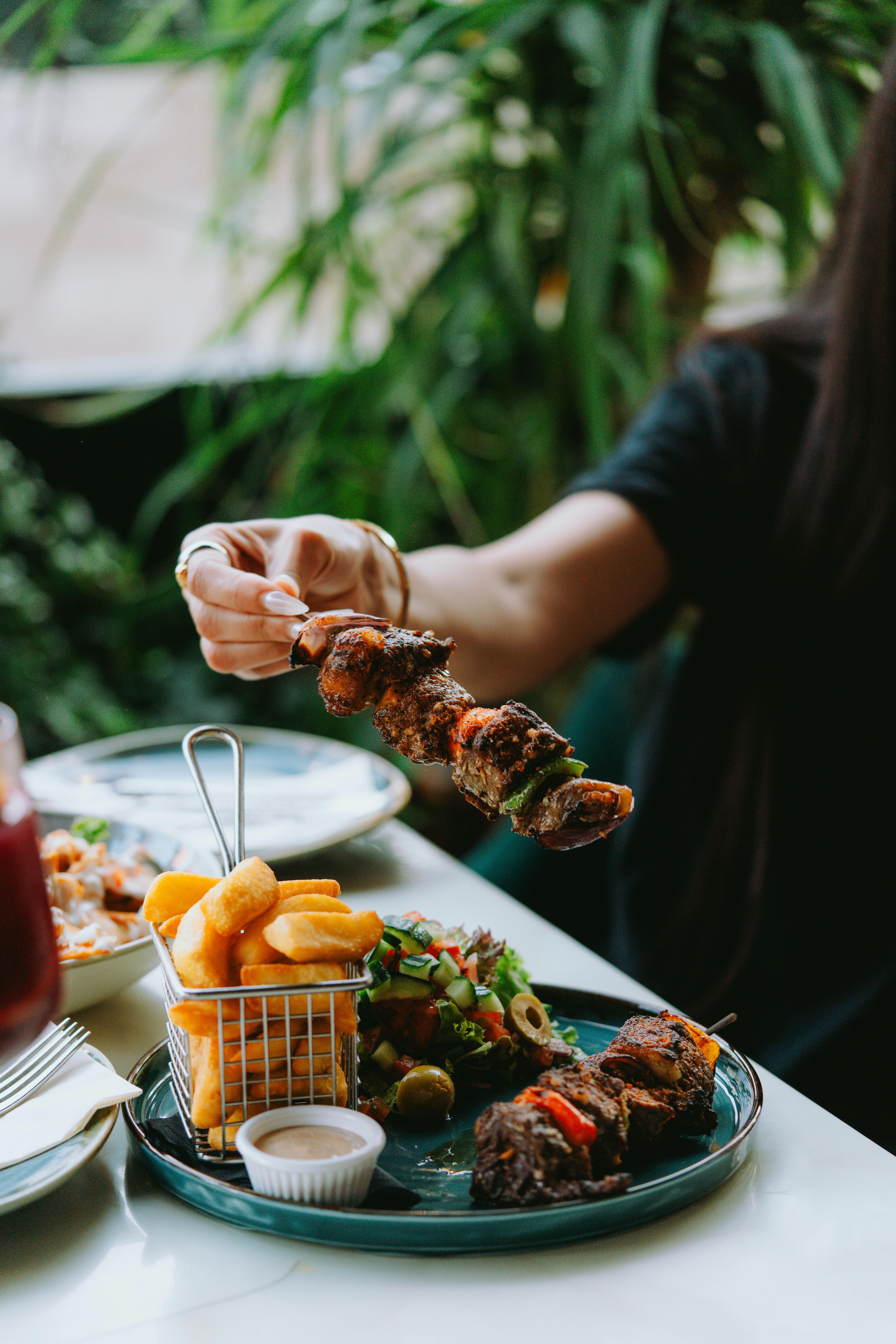 Woman Eating Gyros and French Fries in a Restaurant · Free Stock Photo