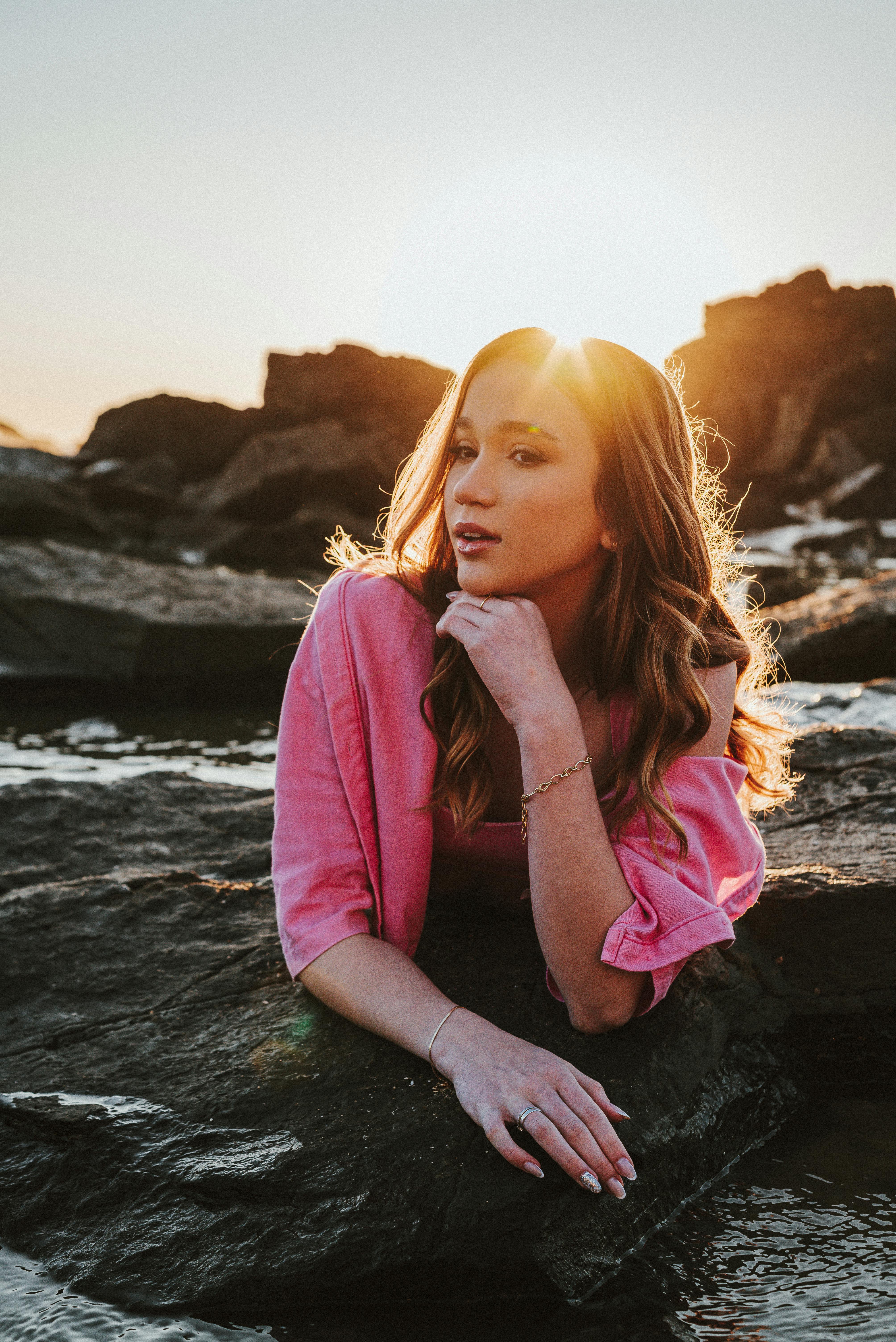 Young Woman Lying on a Rock on the Shore at Sunset · Free Stock Photo