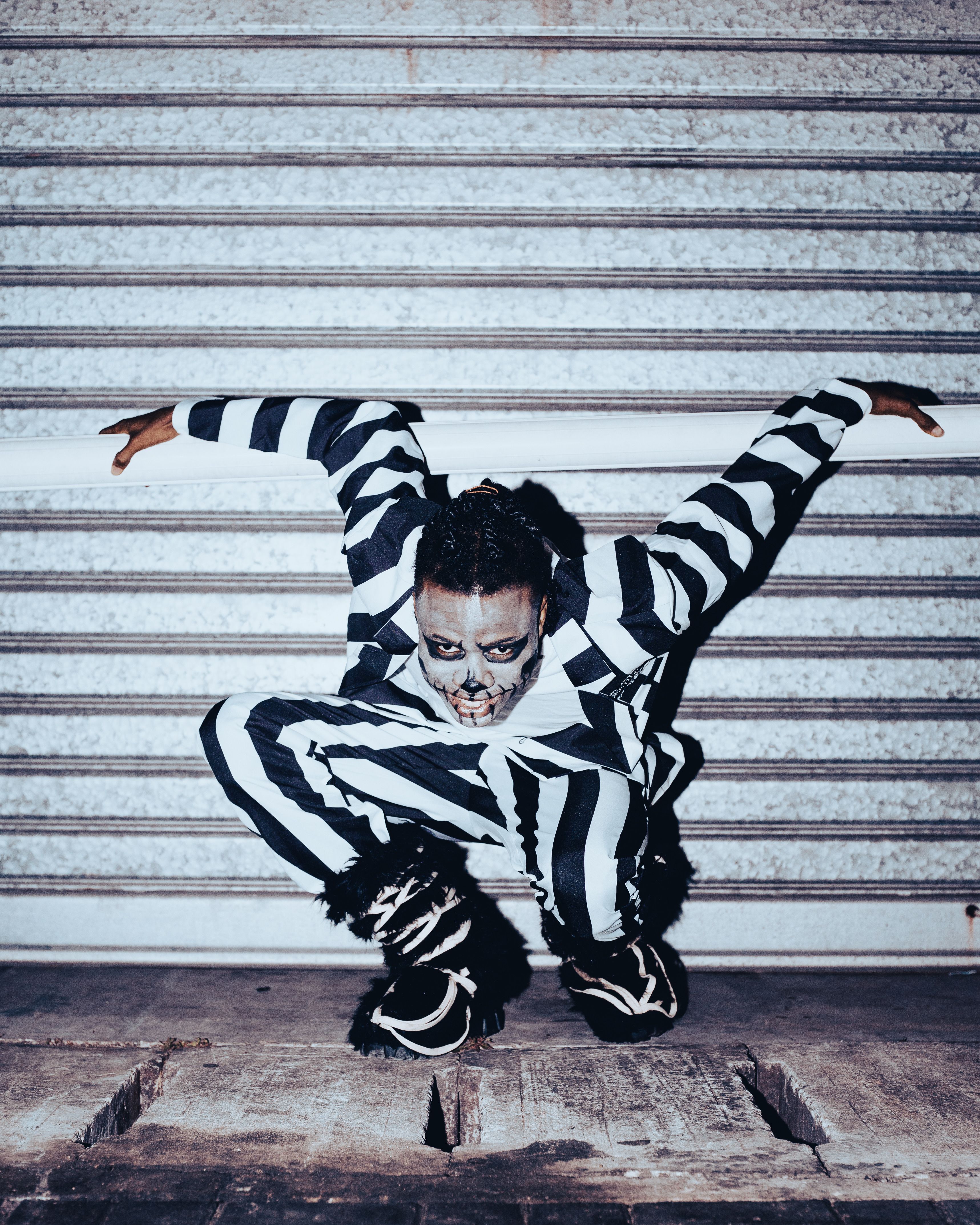 Model in Halloween Costume Squatting and Posing by Wall · Free Stock Photo