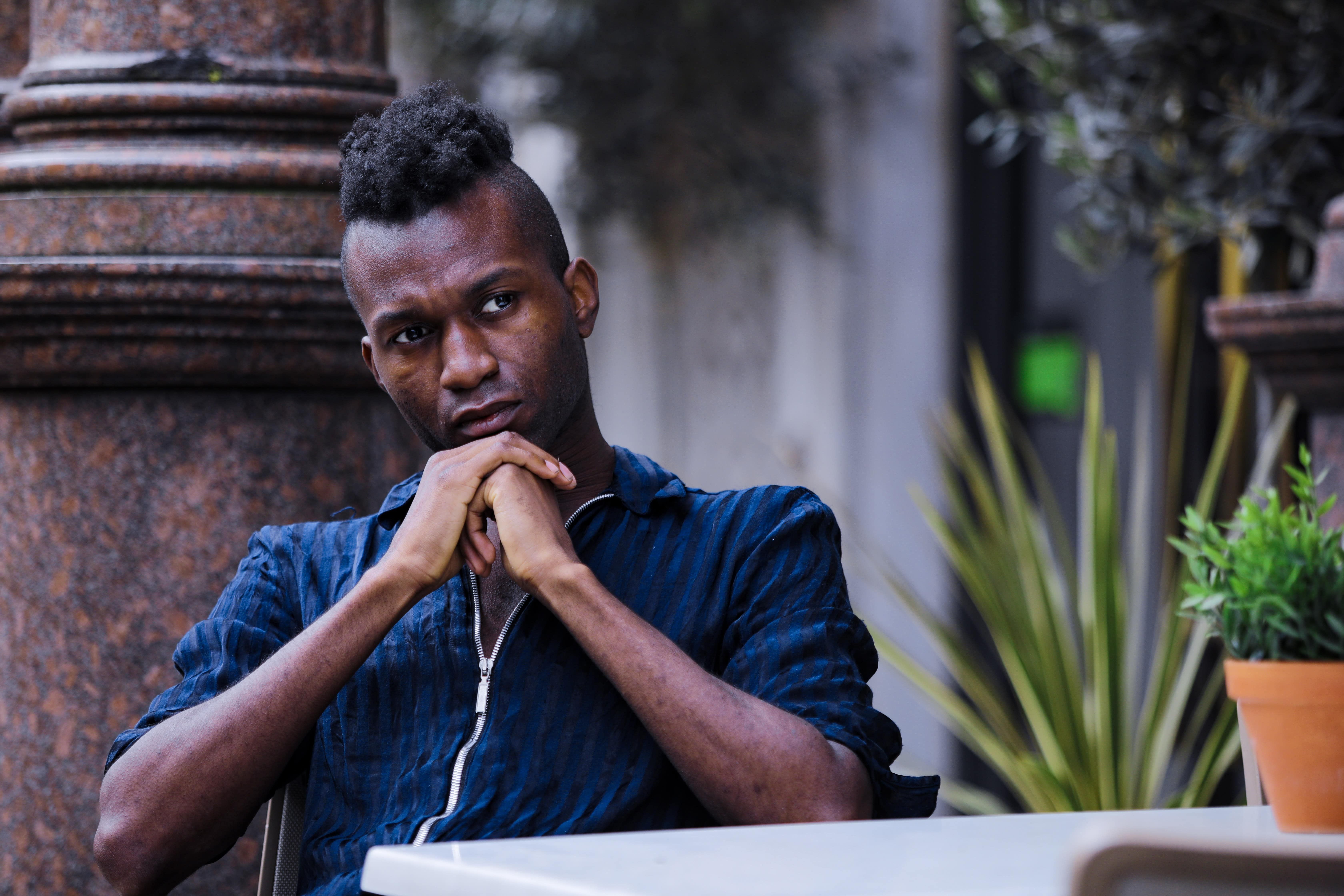 Photo of a Man Sitting at a Table by a Column · Free Stock Photo