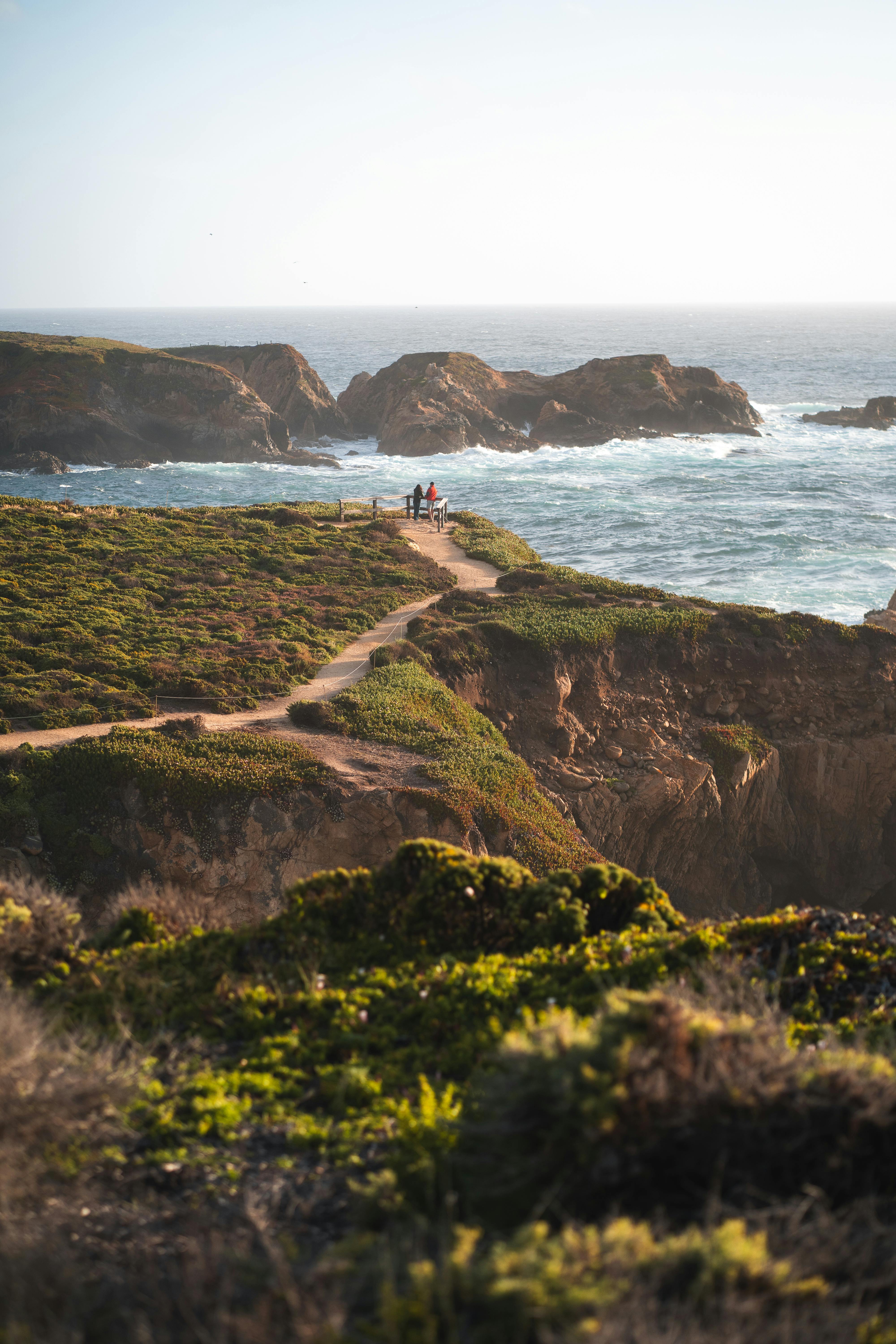 A person walking on a path near the ocean · Free Stock Photo