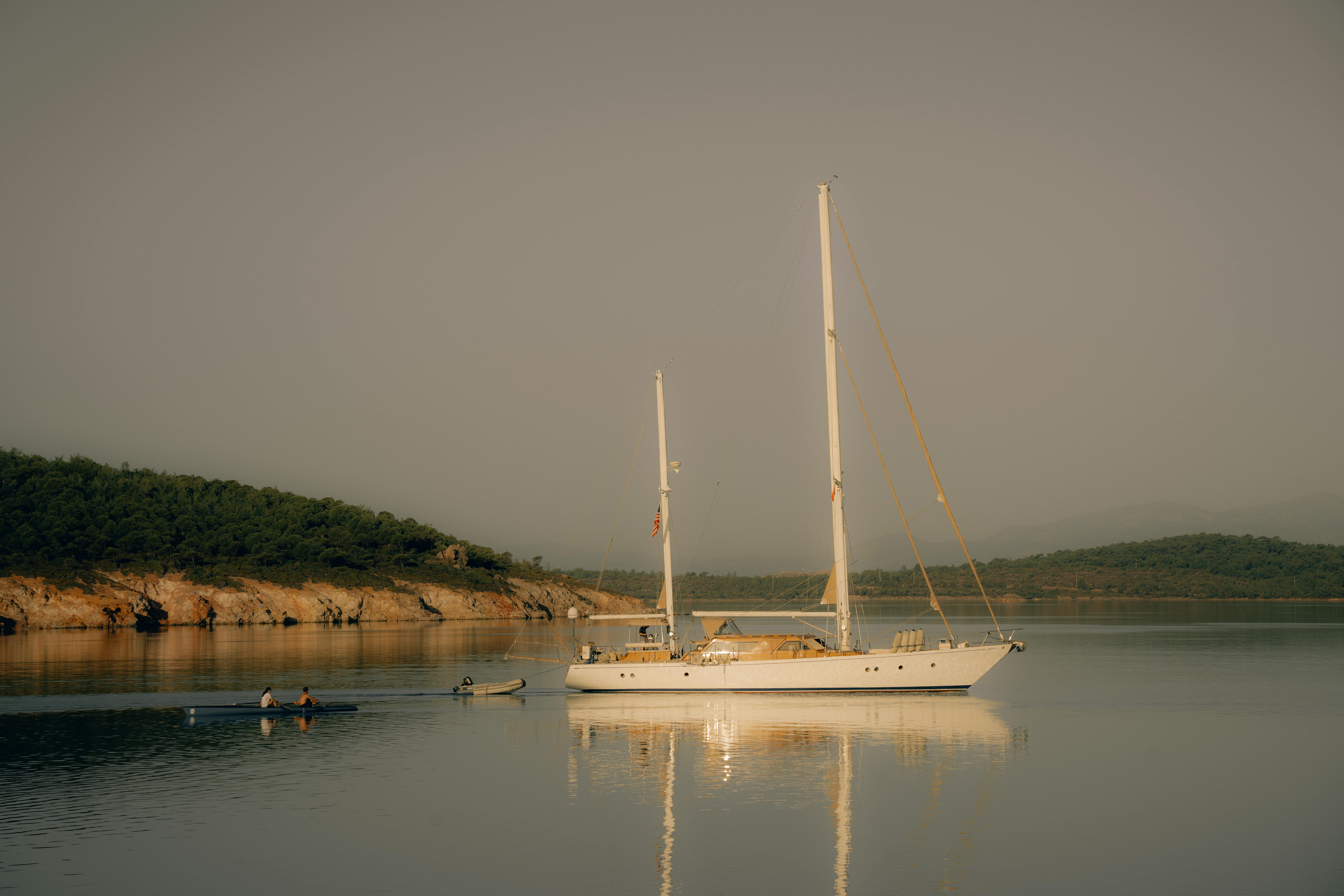 Kayakers Passing by a Sailboat Towing an Inflatable Boat · Free Stock Photo
