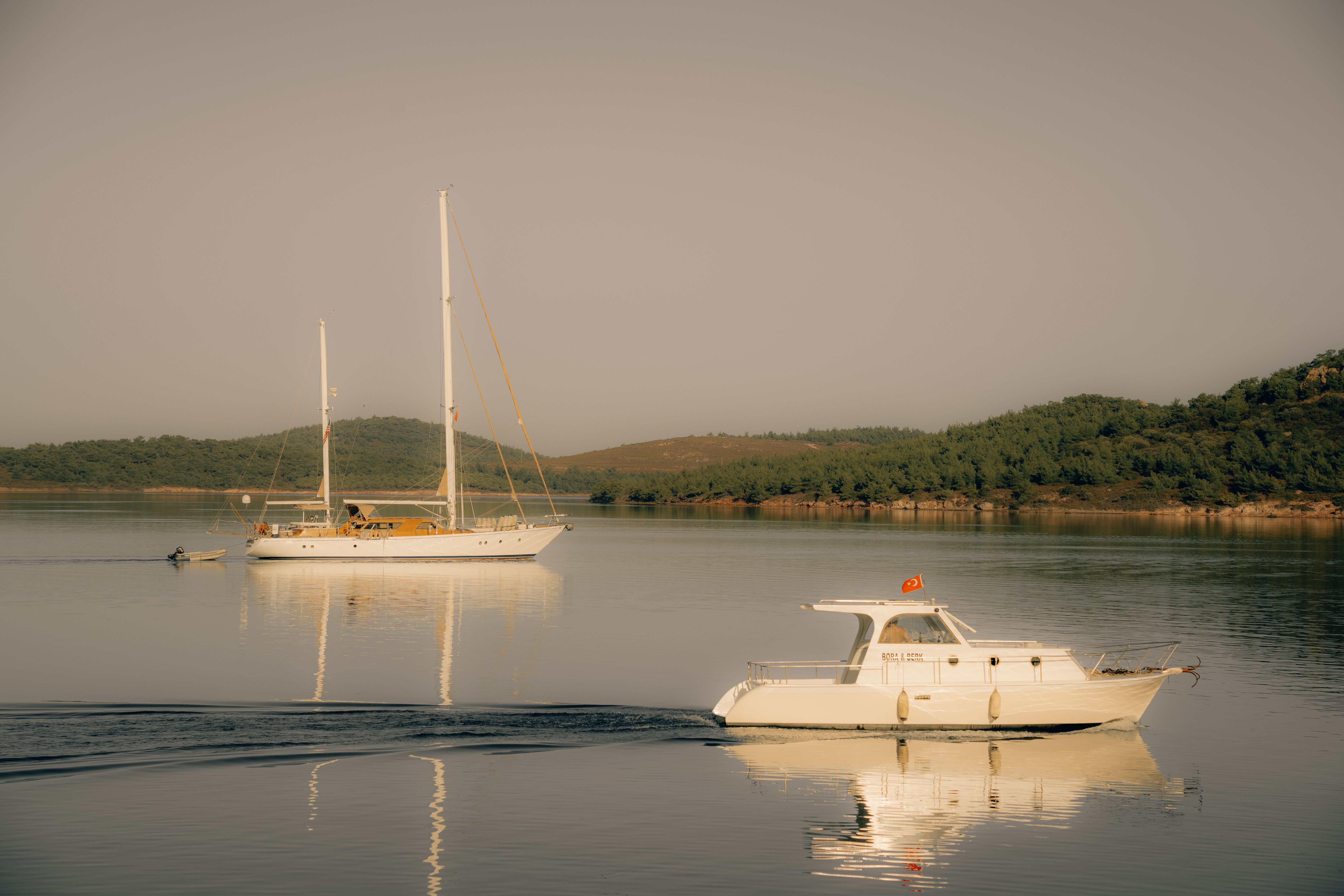 Motorboat Overtaking a Sailboat at the Sea by the Coast · Free Stock Photo