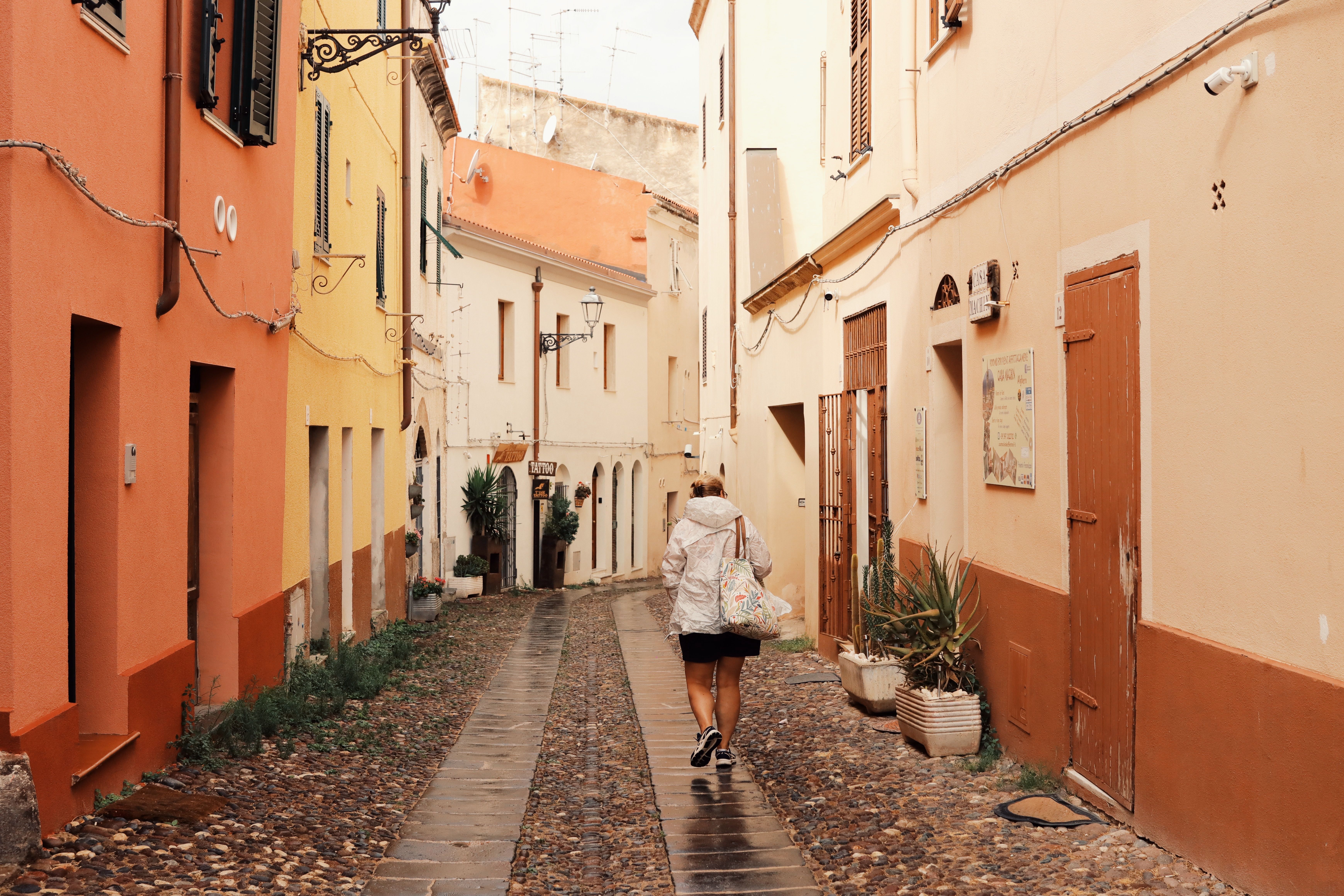Back View of a Woman Walking in an Alley between Houses · Free Stock Photo