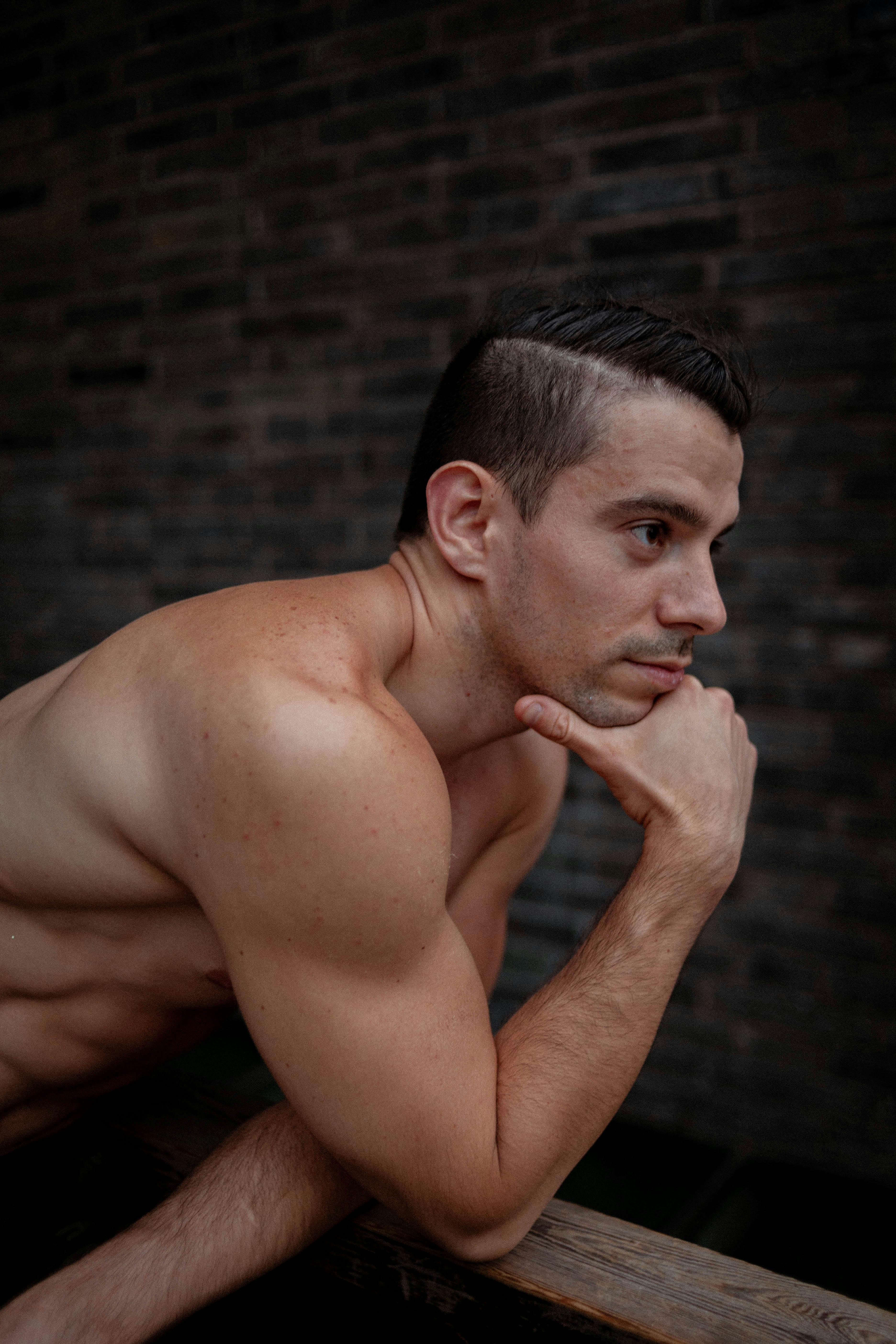 Shirtless Muscular Man Leaning on a Wooden Surface · Free Stock Photo