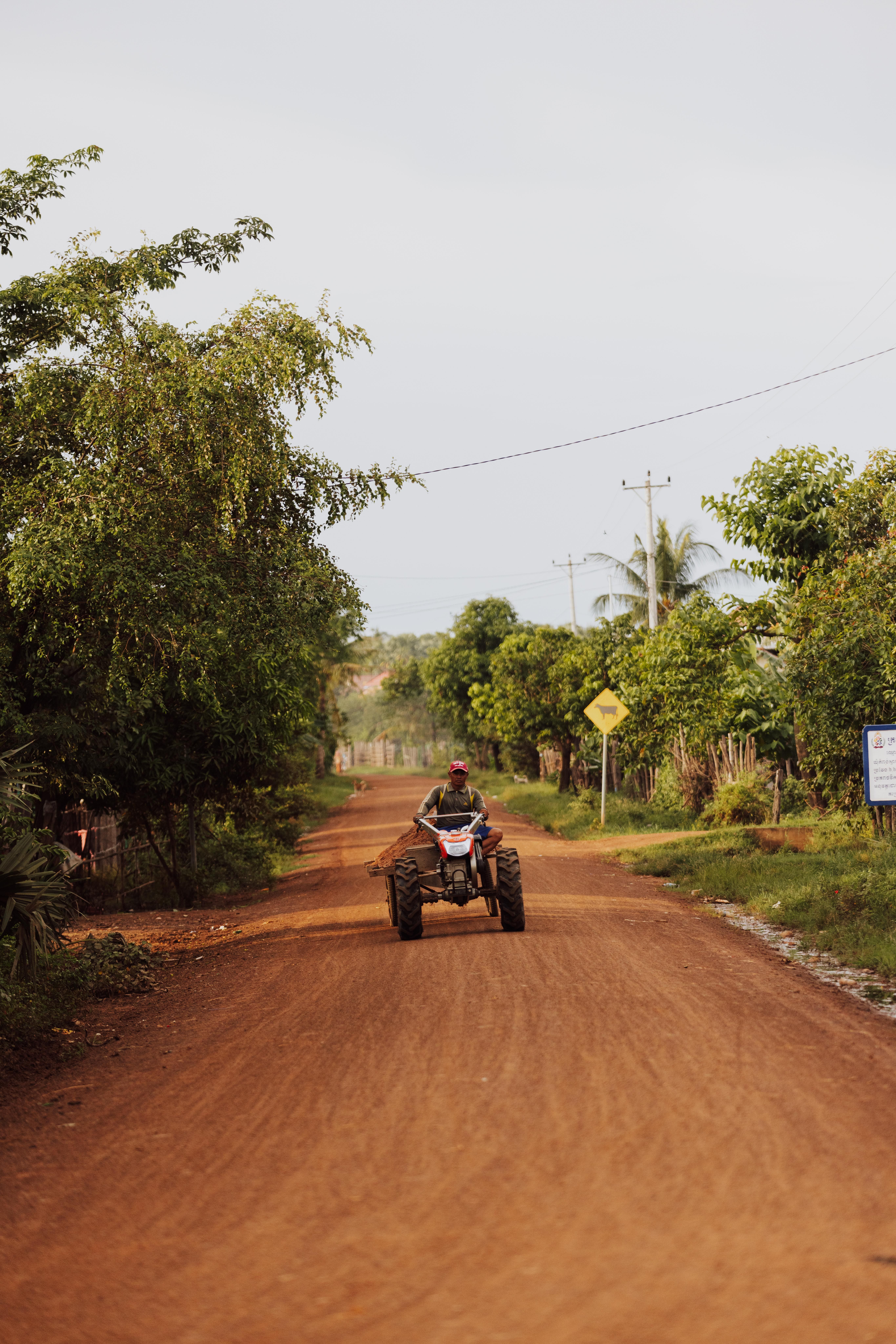 Man Riding on a Small Tractor on a Dusty Village Road · Free Stock Photo