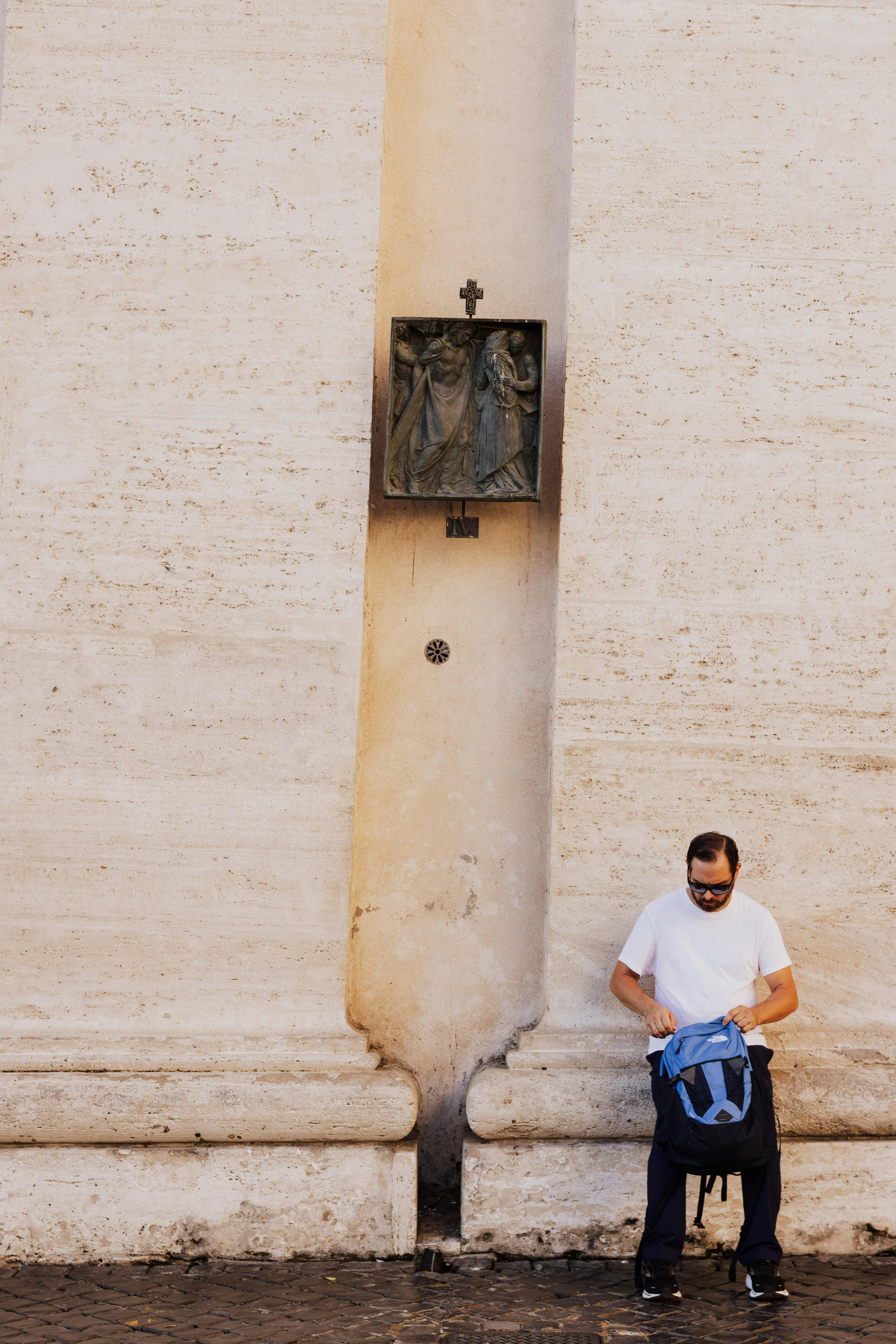 A Man with a Backpack Sitting under a Religious Bas Relief · Free Stock ...