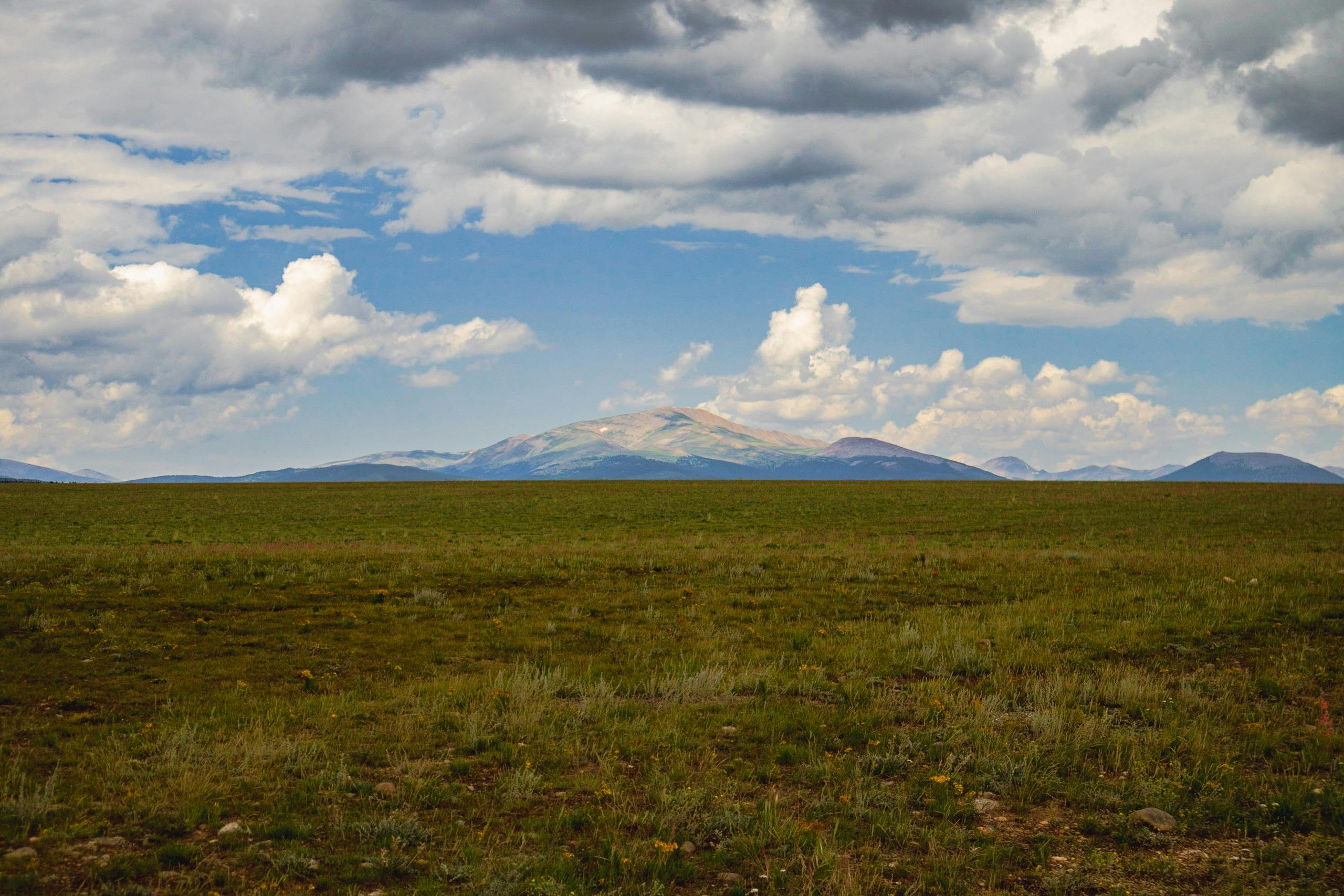 Green Grassland and Rock Formation behind · Free Stock Photo