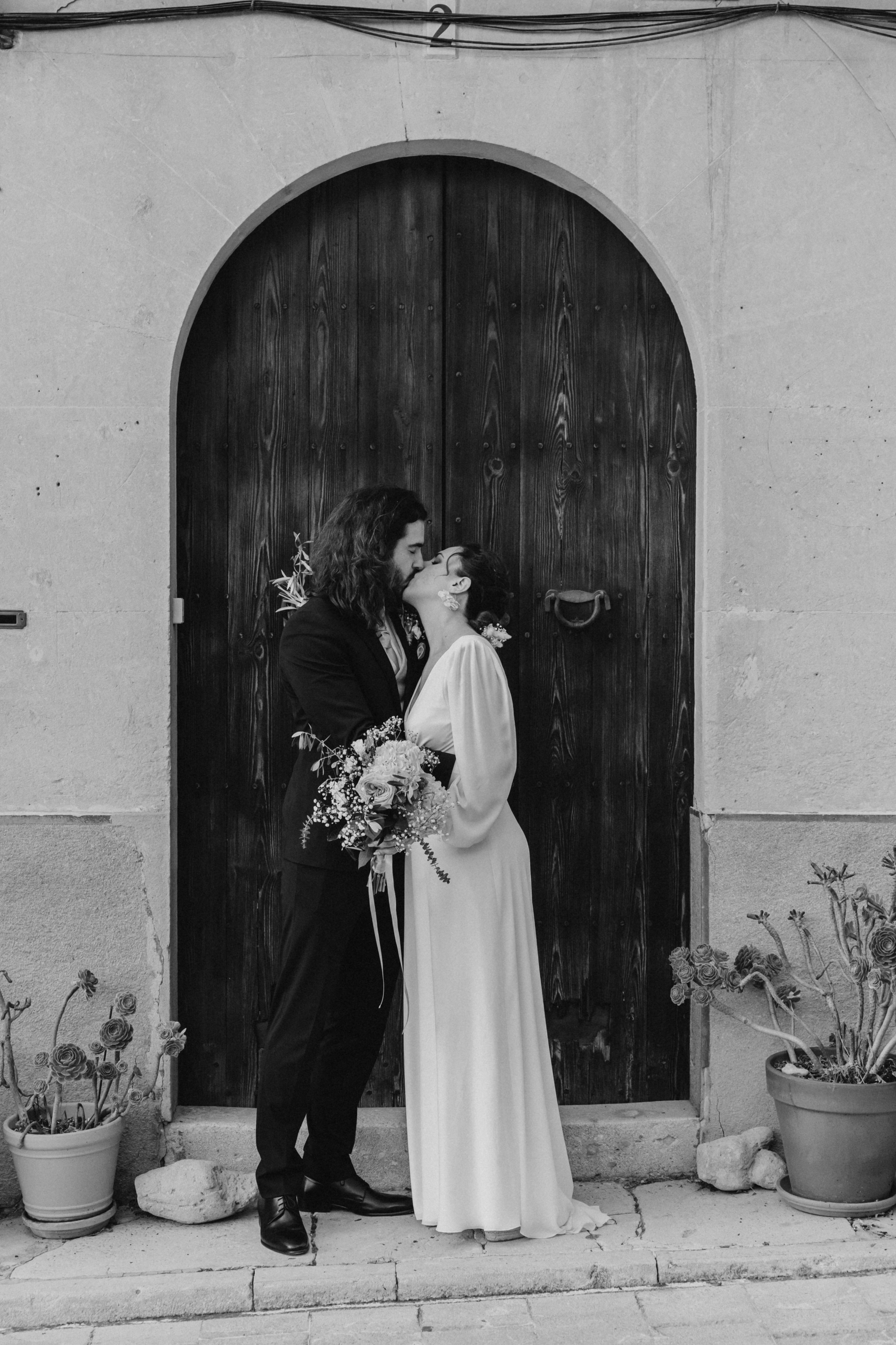 Bride and Groom Kissing in front of Old Wooden Door · Free Stock Photo