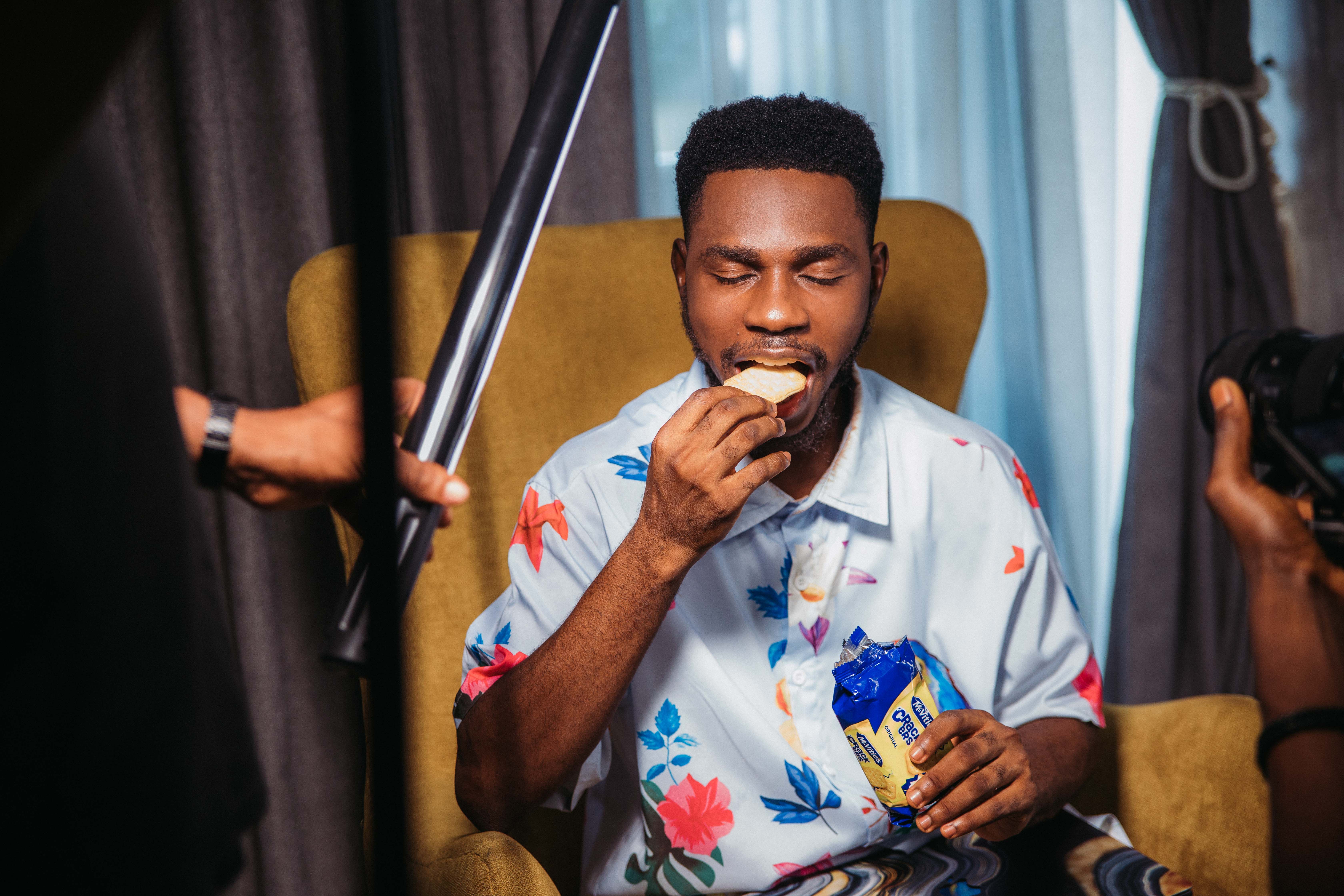 Man Sitting and Eating Crackers with Eyes Closed · Free Stock Photo