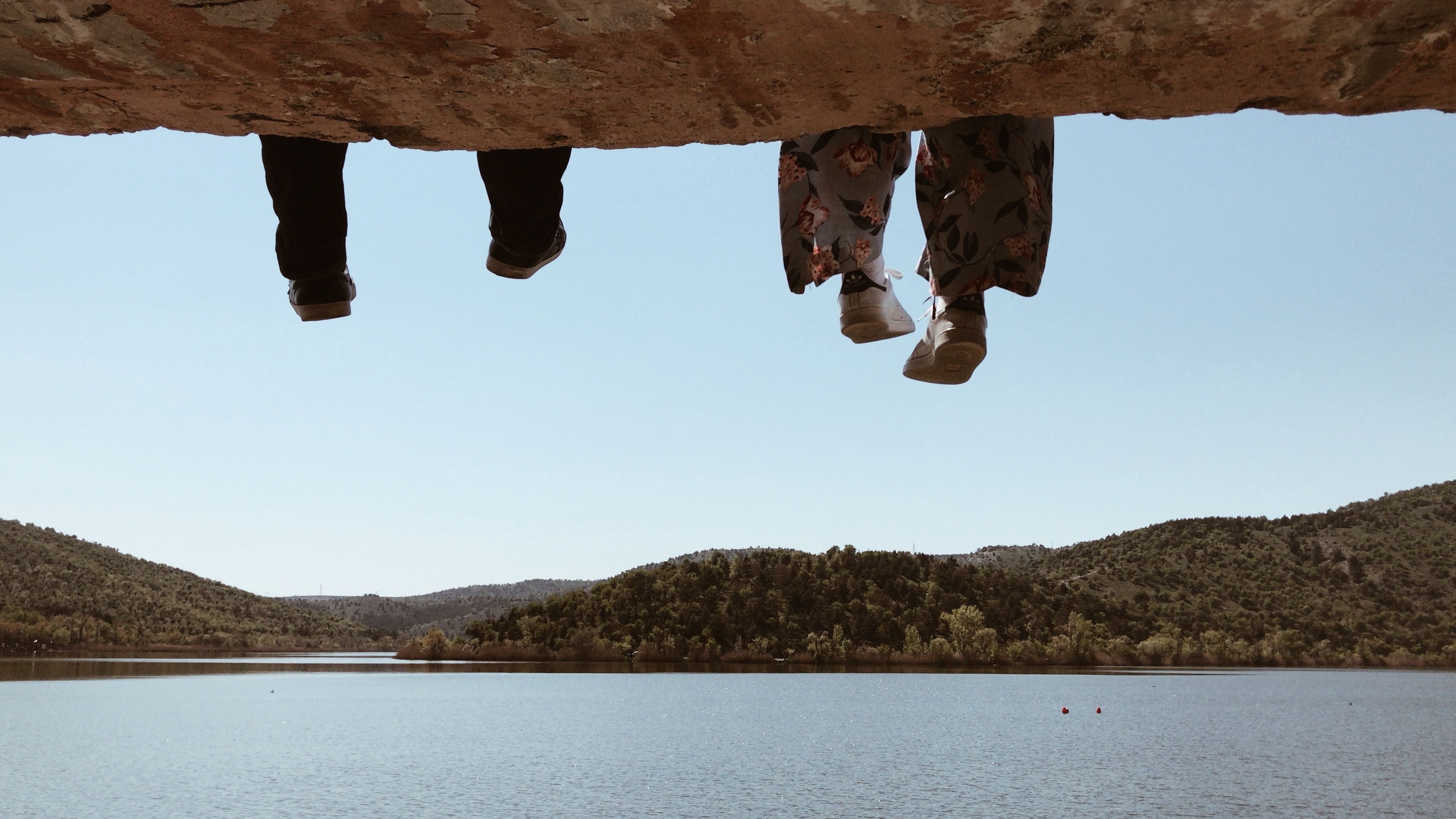 Dangling Feet of People Sitting on Bridge over a Lake · Free Stock Photo