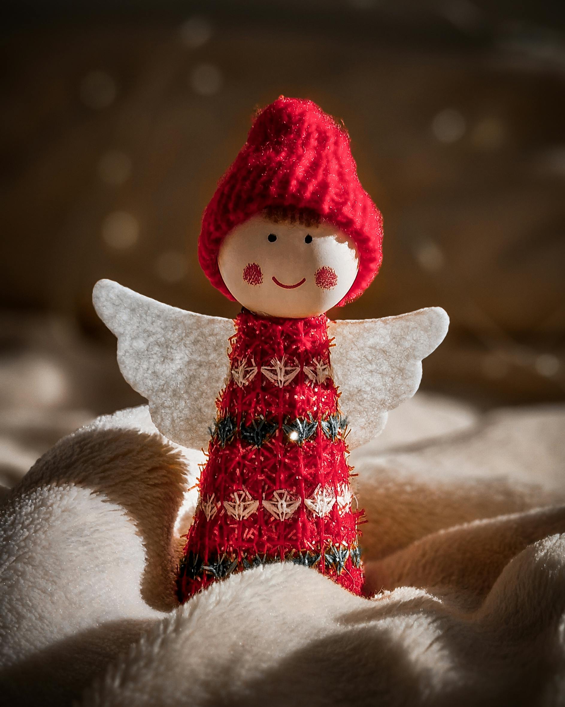 Close-up of a cute red Christmas angel statuette on a fluffy white ...