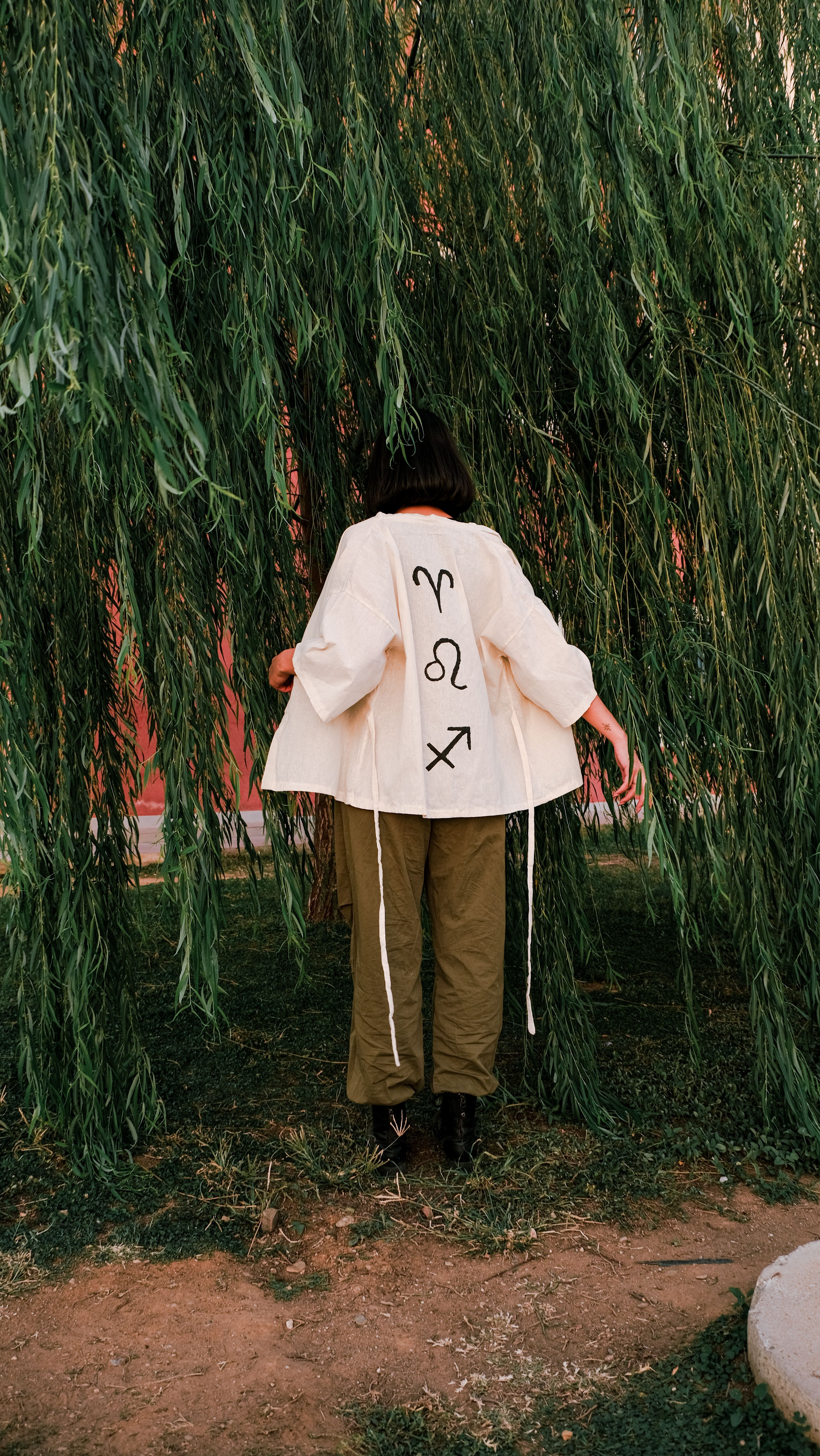 Back View of a Woman Wearing a Coat with Zodiac Symbols, Standing under ...