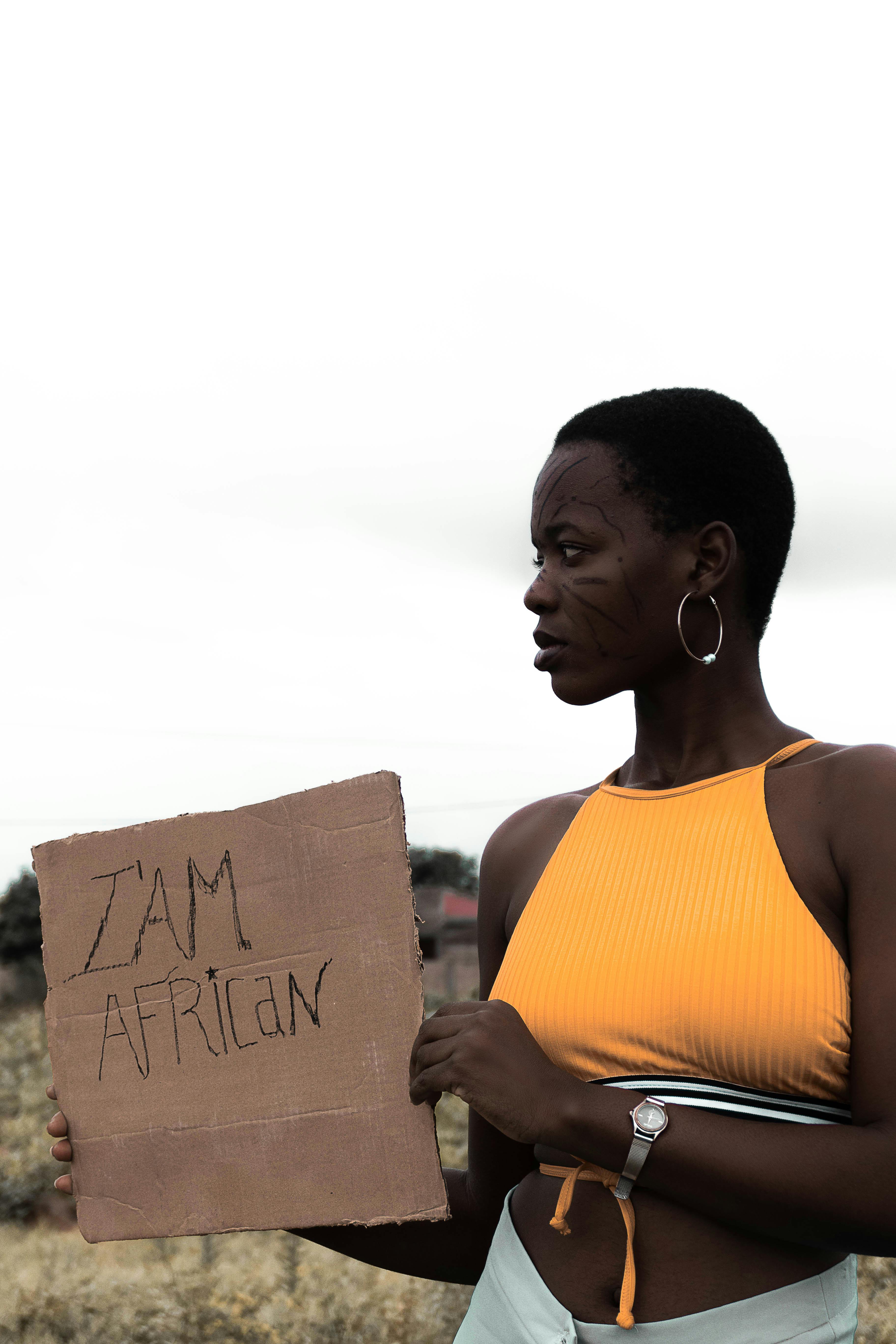 Young Woman Holding a Piece of Cardboard with a Text "I am African ...
