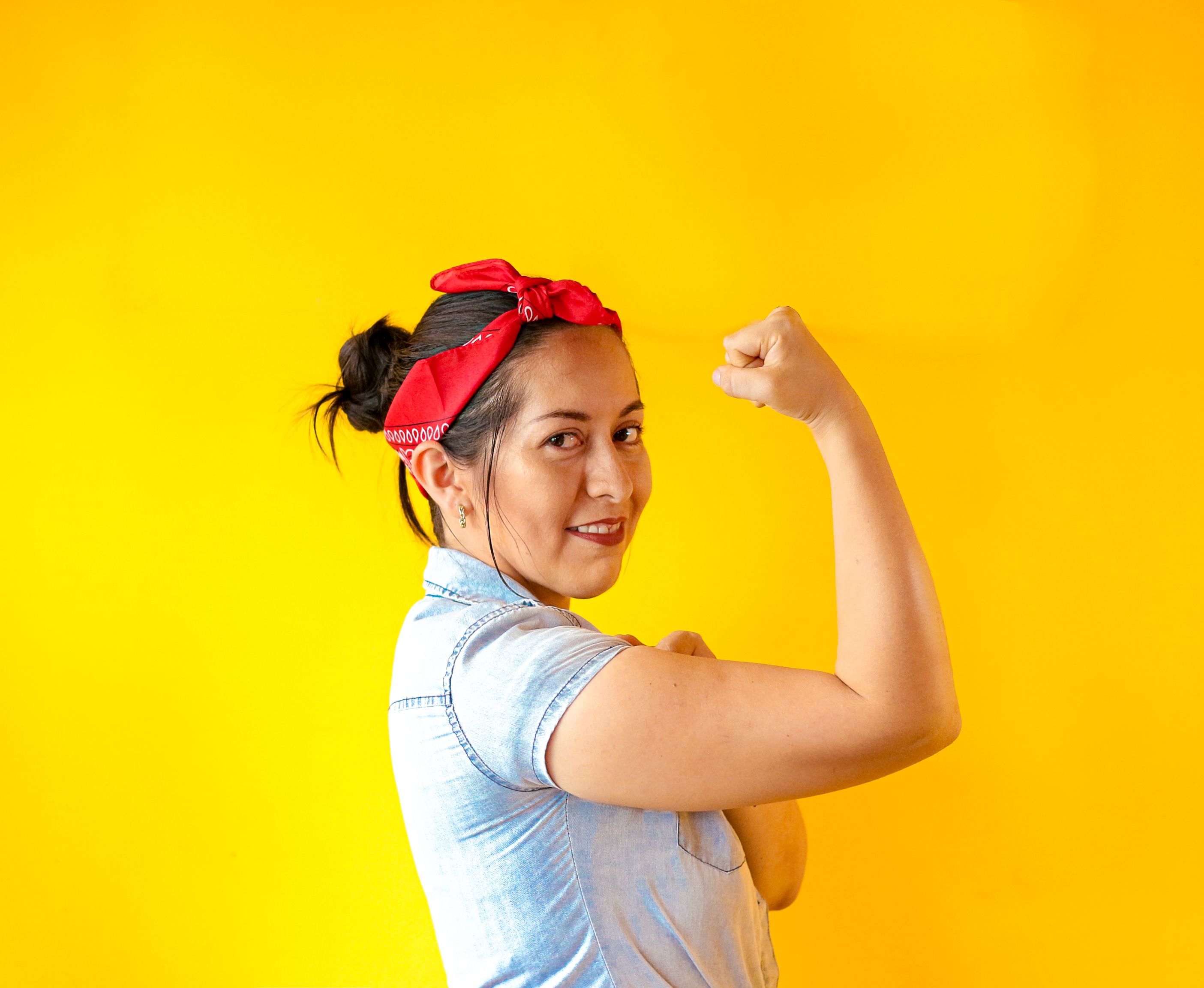 Studio Shot of a Woman Presenting Arm Muscles against a Yellow ...