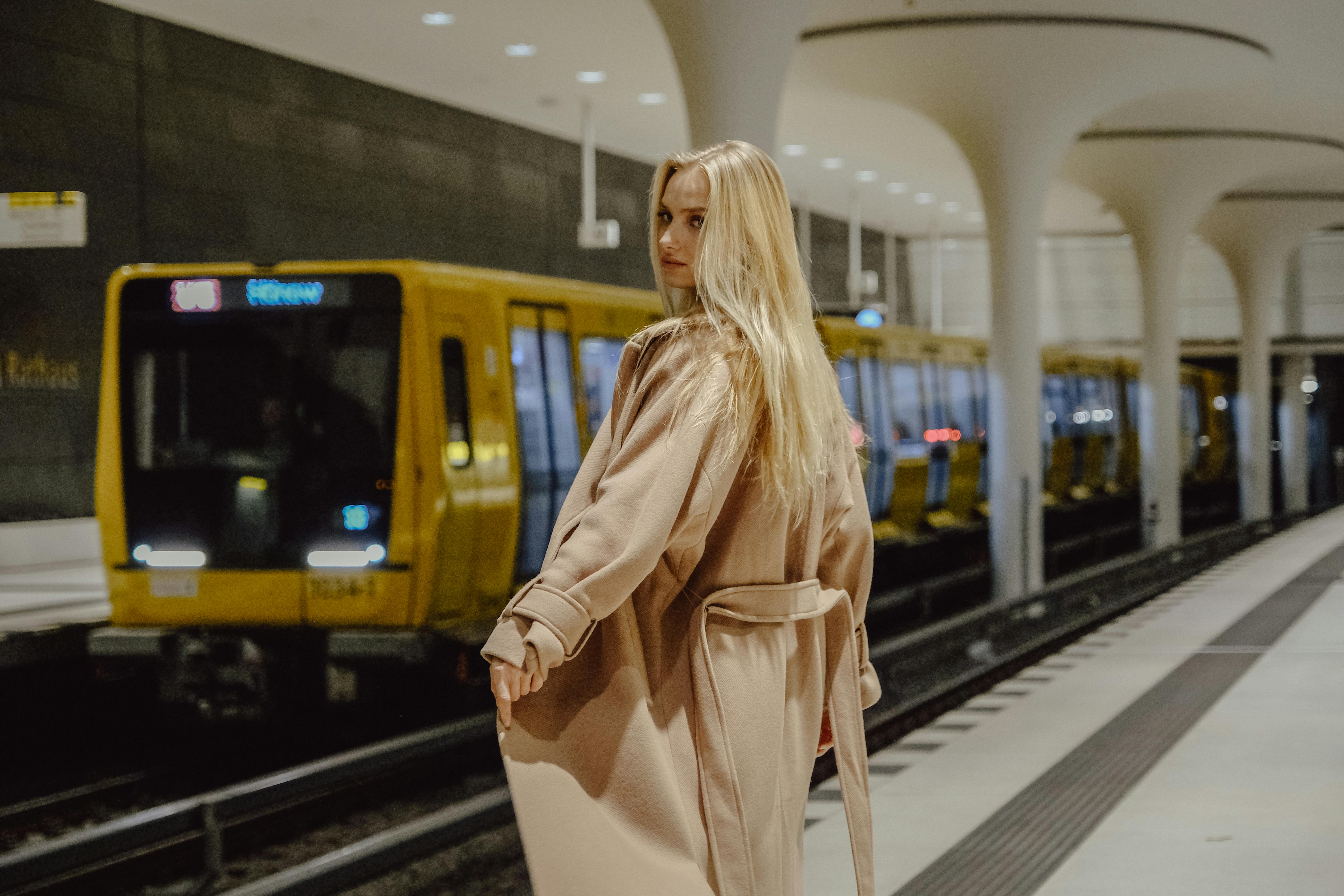 Blonde Woman in Coat Standing with Metro Train behind · Free Stock Photo