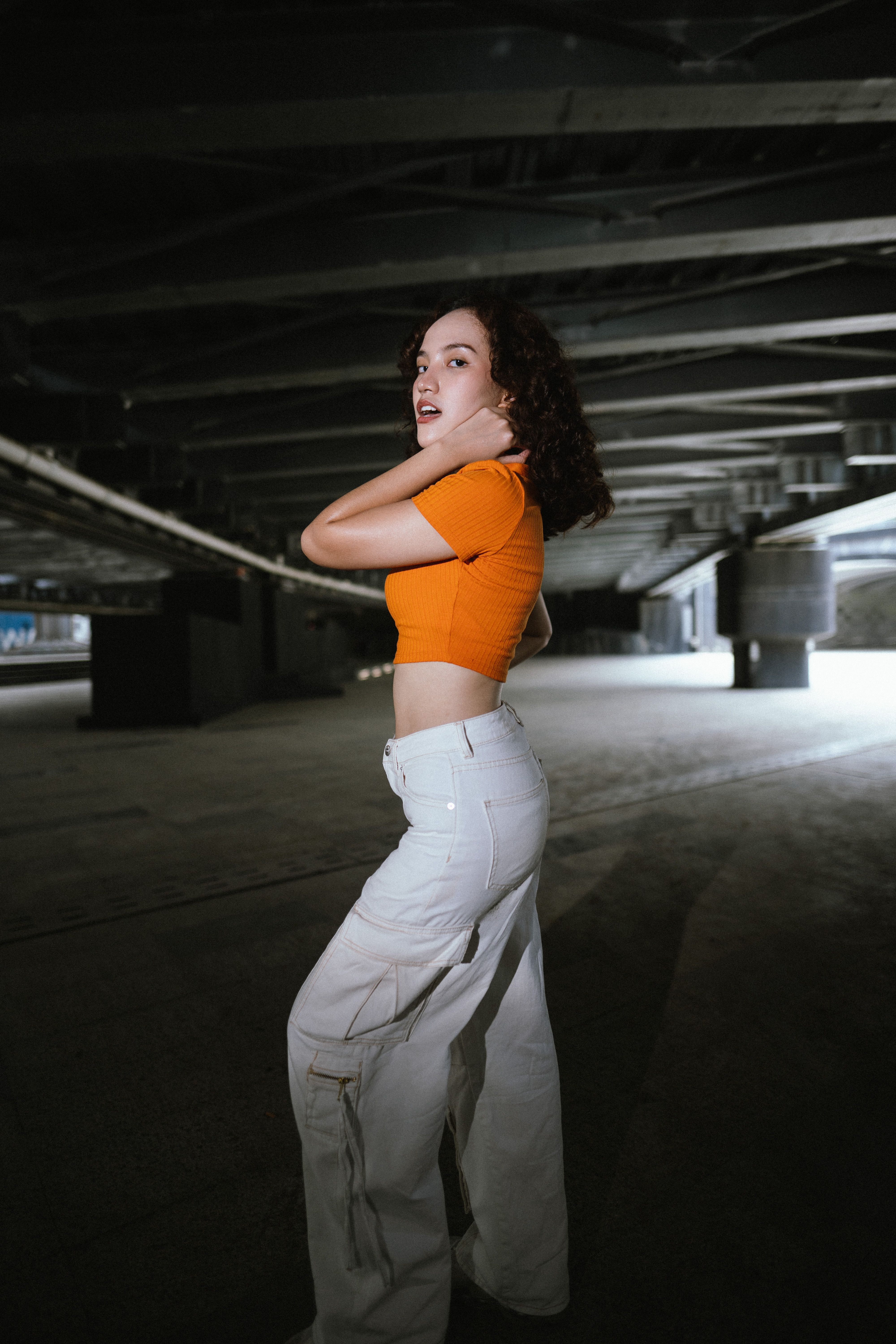 Woman in White Pants Standing under a Bridge · Free Stock Photo