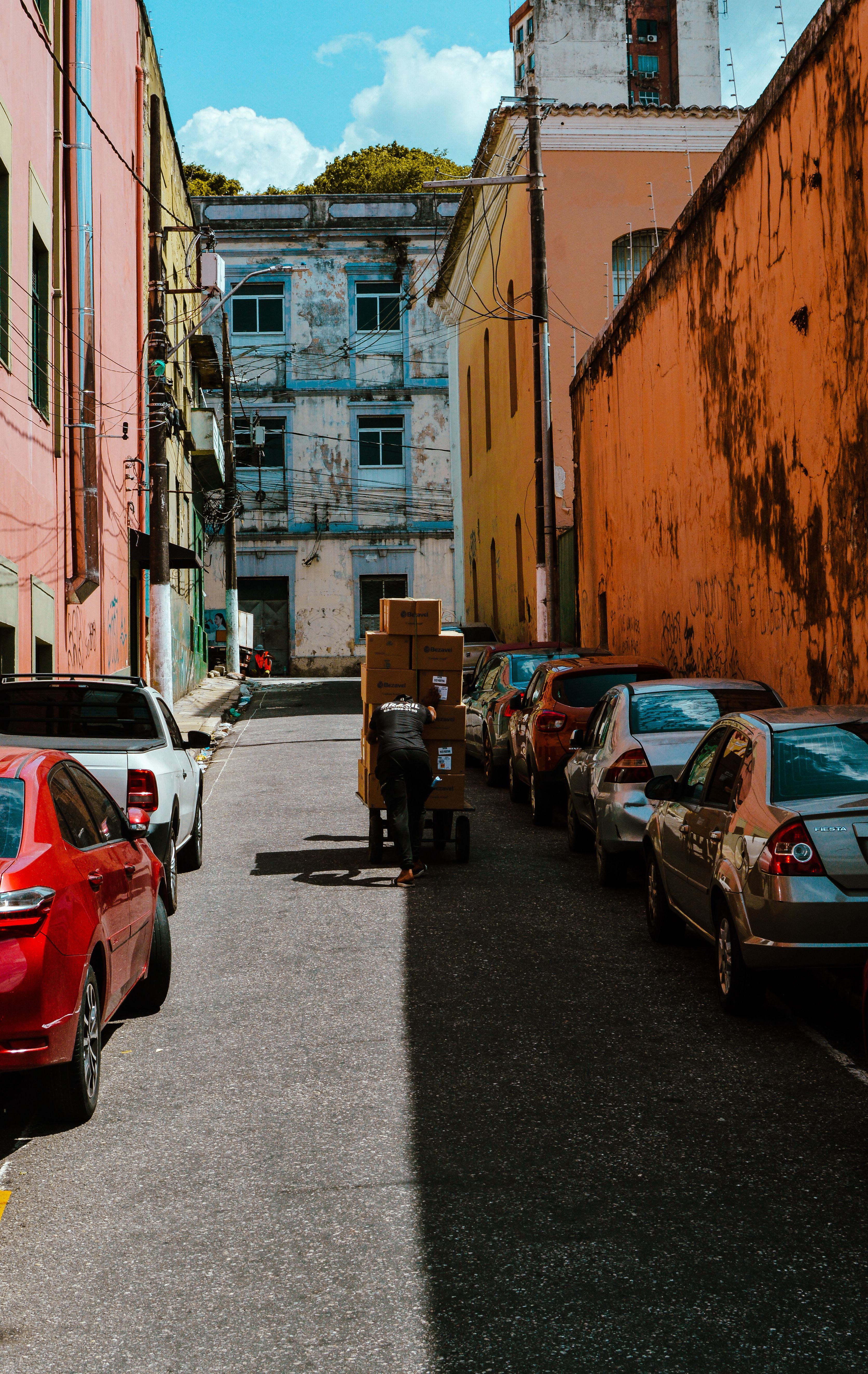 Person Walking with Boxes on Trailer on Street in Town · Free Stock Photo