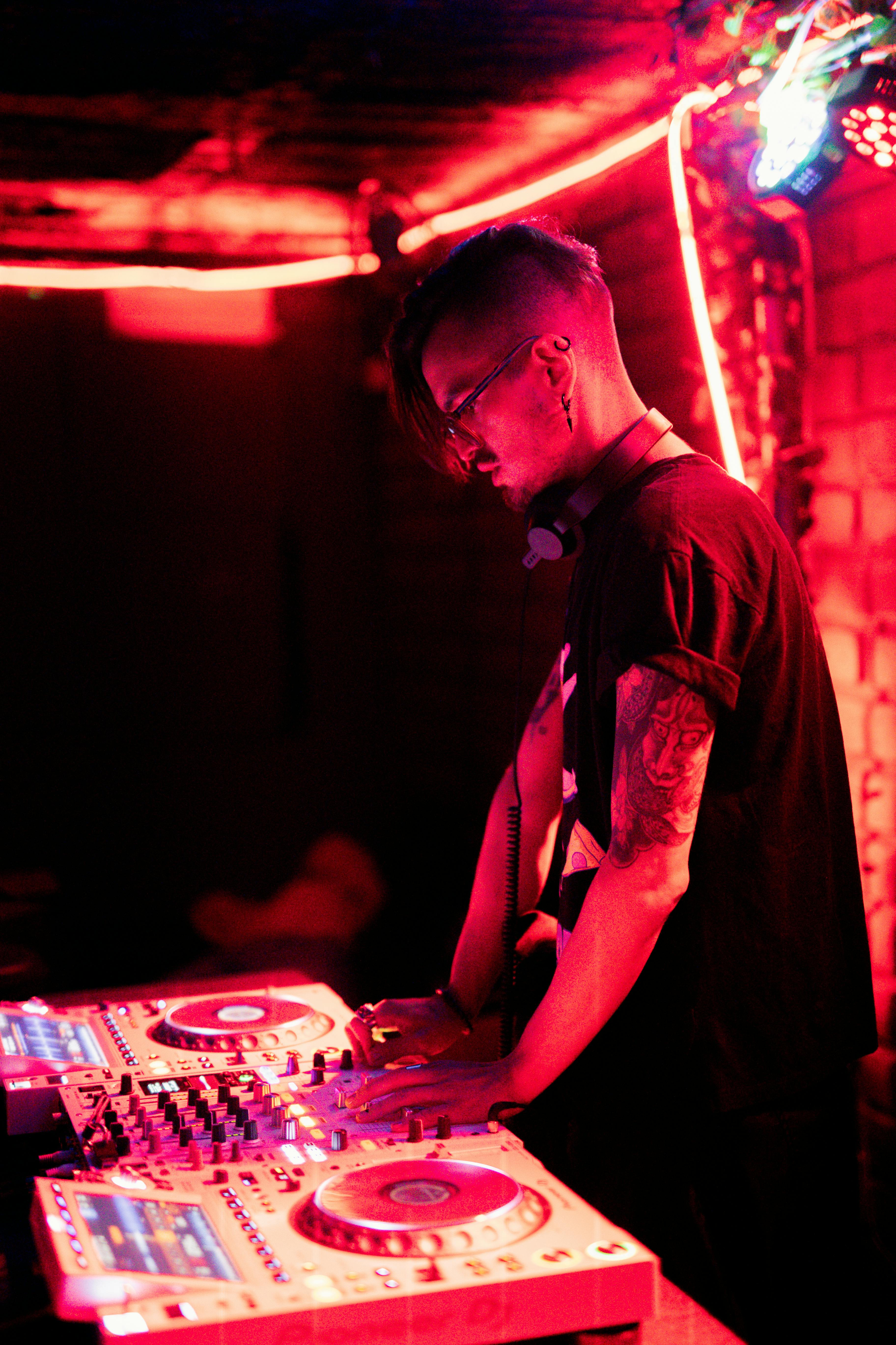 DJ Standing by Sound Mixer on Stage in Nightclub · Free Stock Photo