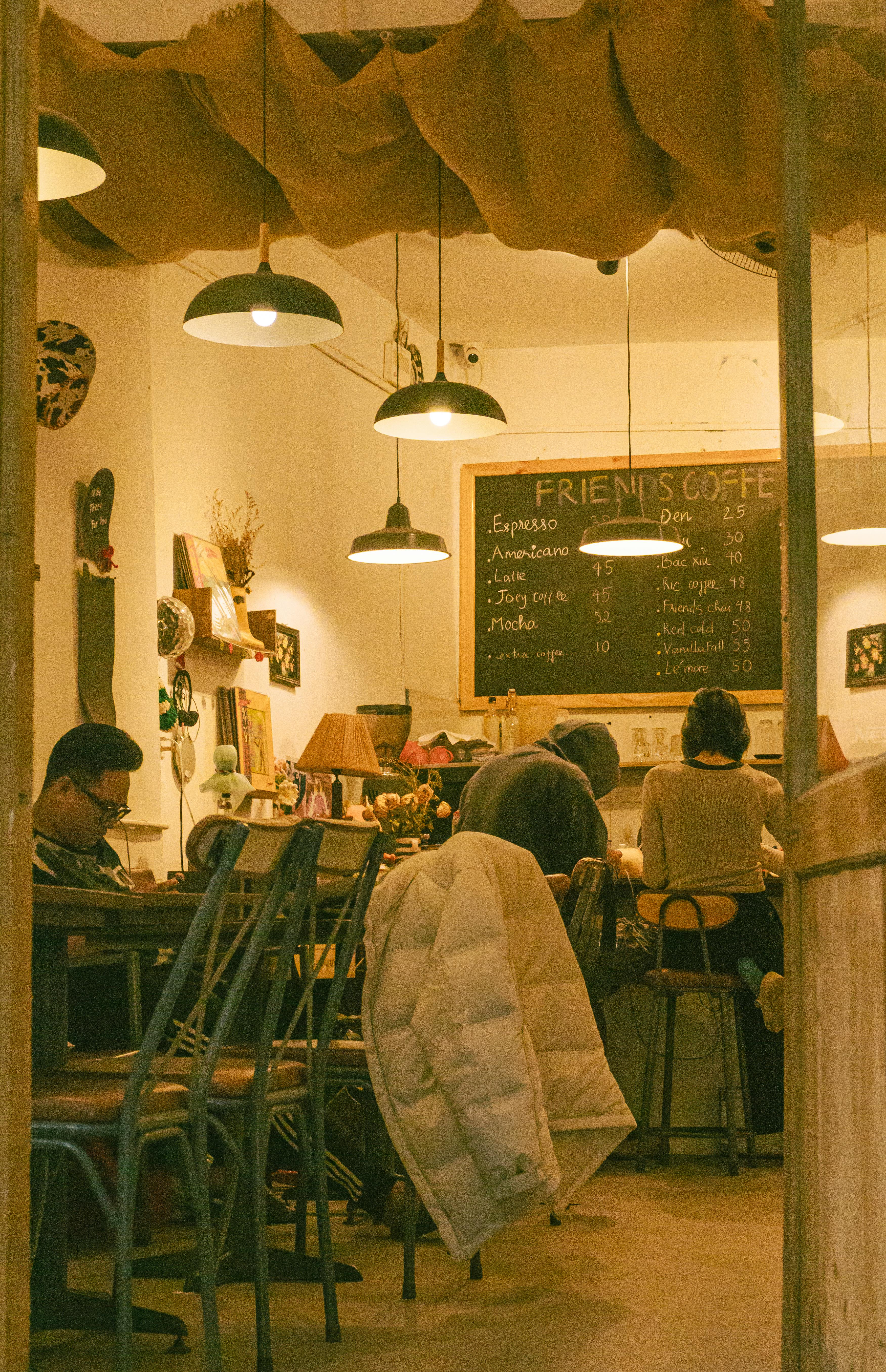 People Sitting in a Cafe with Warm Lighting · Free Stock Photo