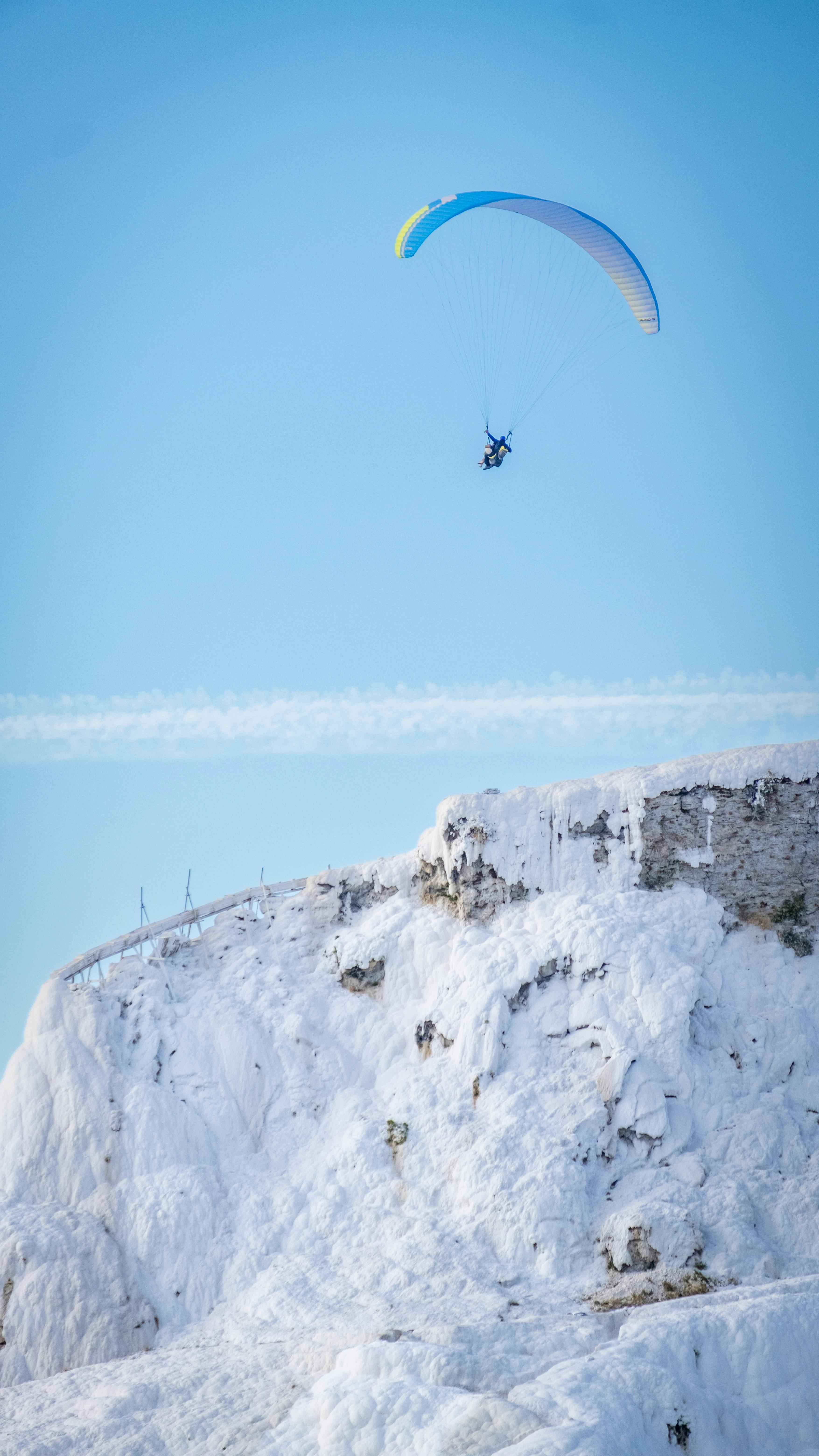 Man Flying on Parachute Near Green Trees · Free Stock Photo