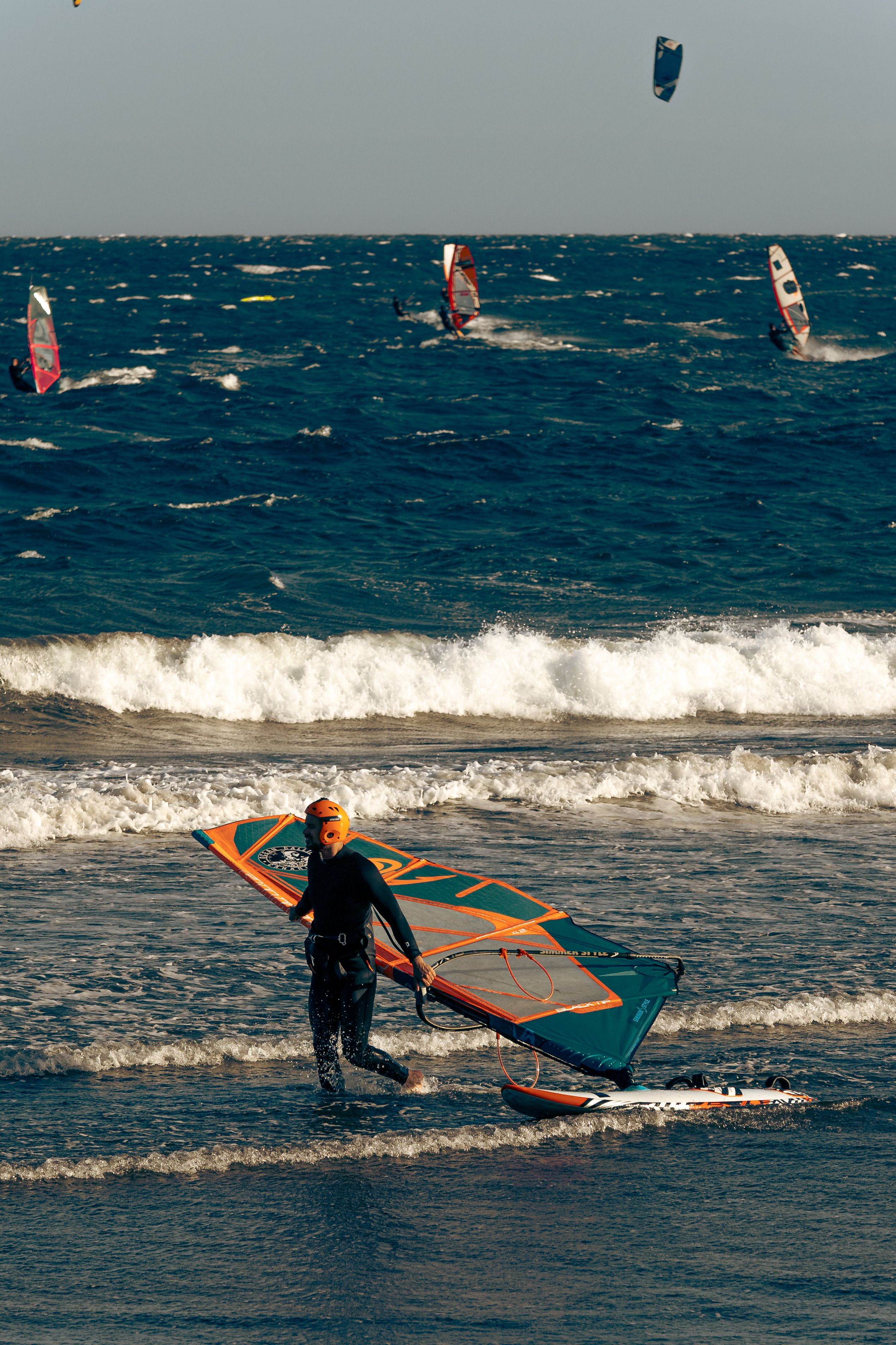 Man Walking with a Windsurf Sail on a Beach · Free Stock Photo