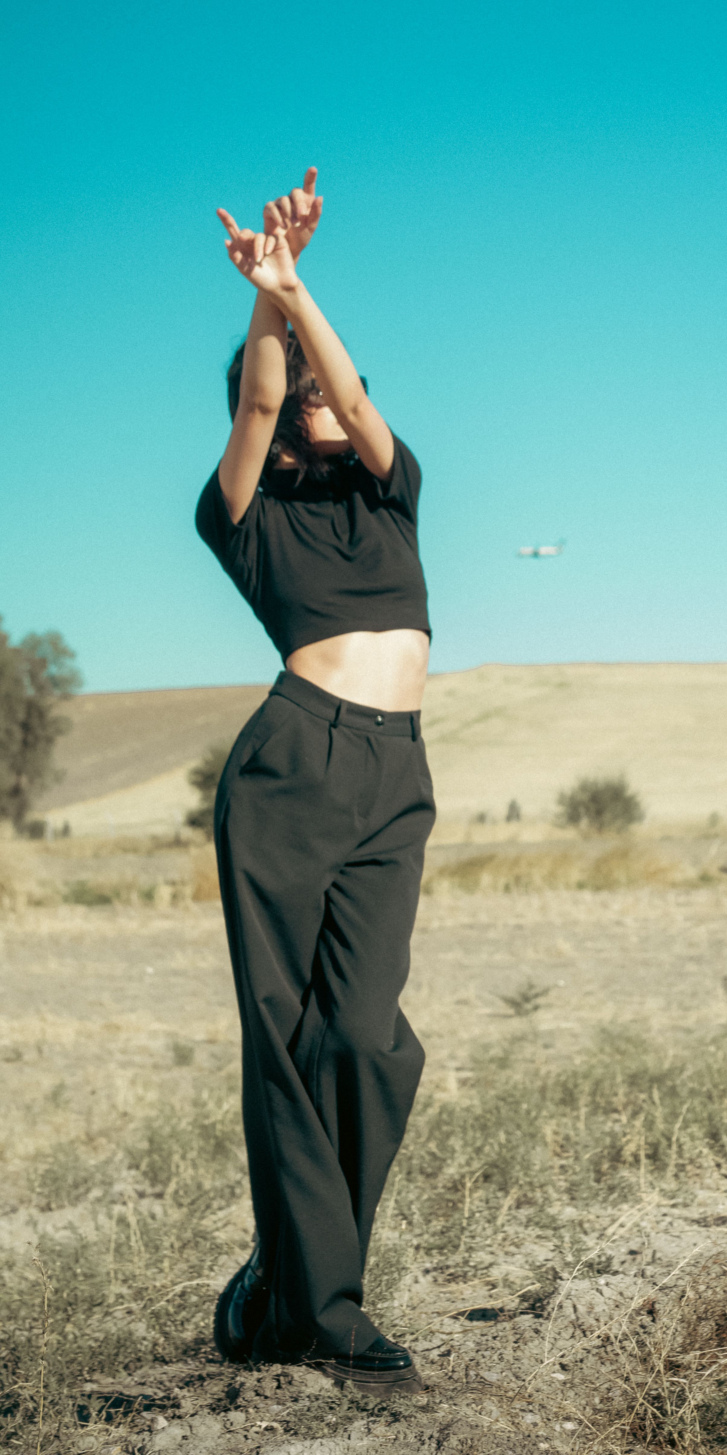 Model in Black Clothes Standing with Arms Raised on Grassland · Free ...