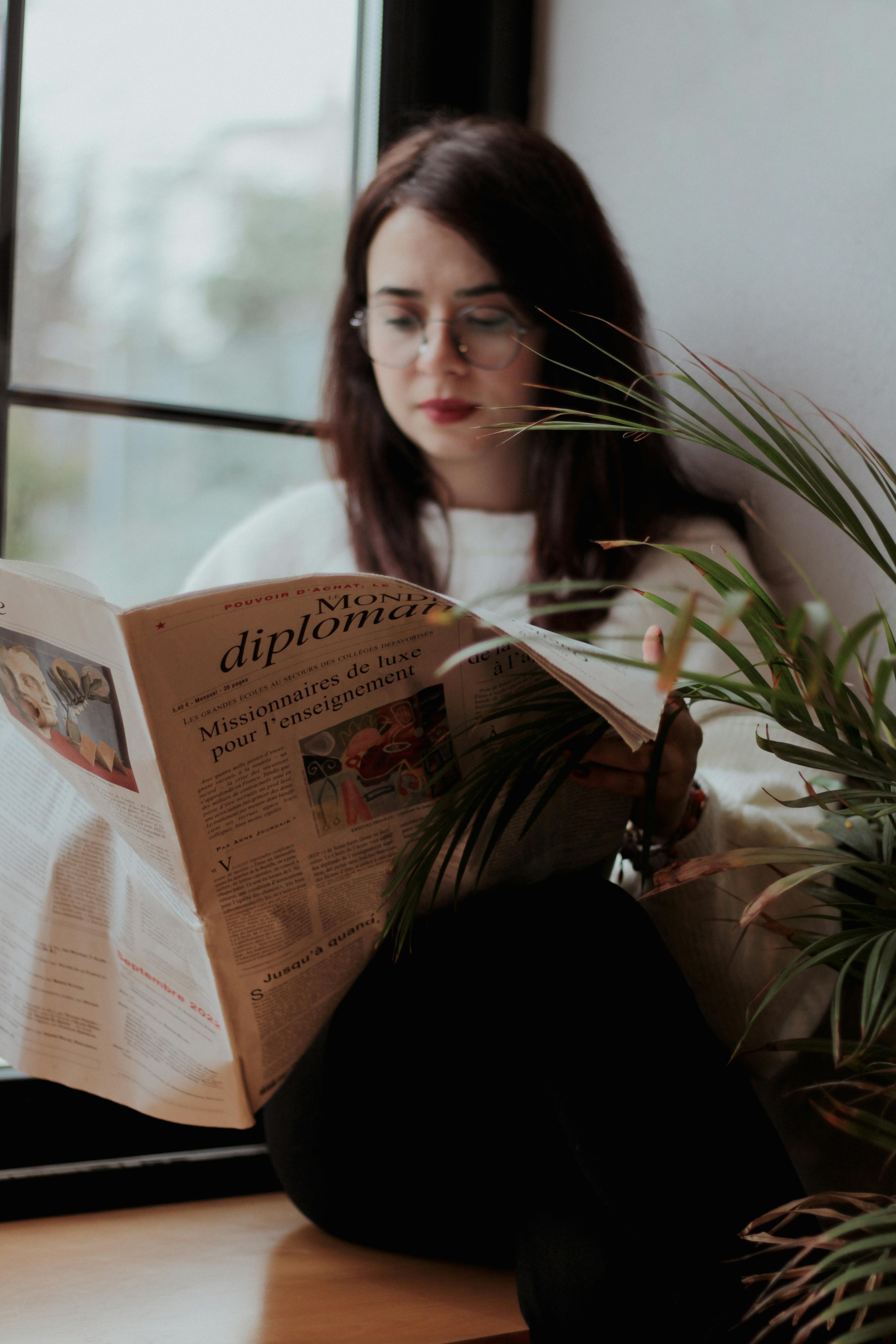 Woman Sitting by the Window and Reading a Newspaper · Free Stock Photo