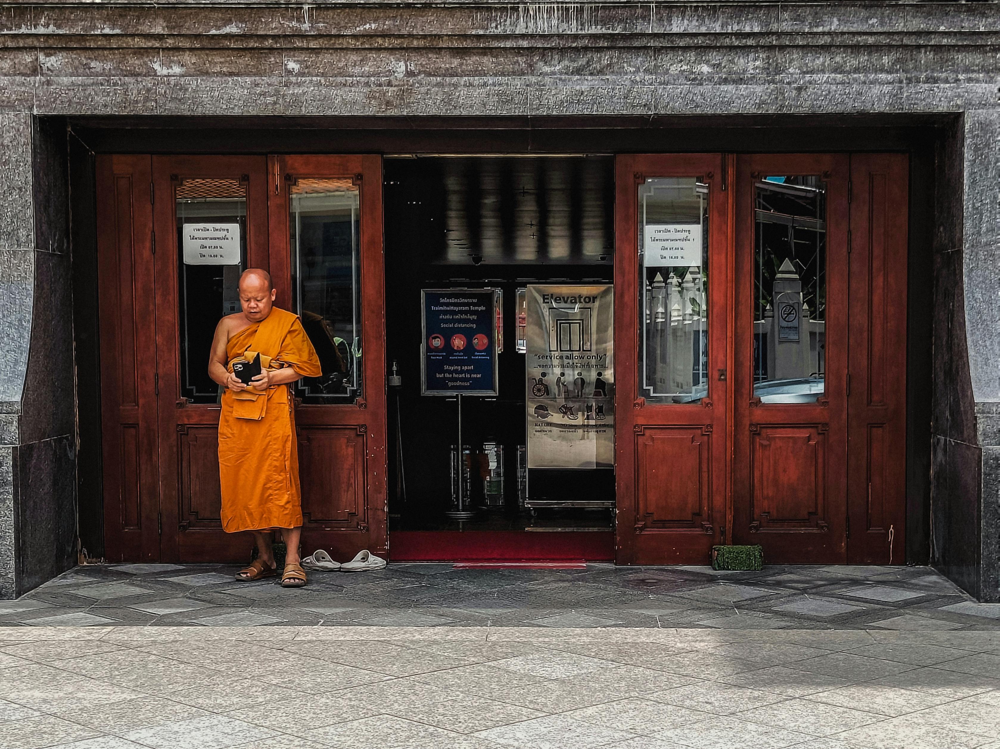Monk Walking Towards Concrete Building · Free Stock Photo