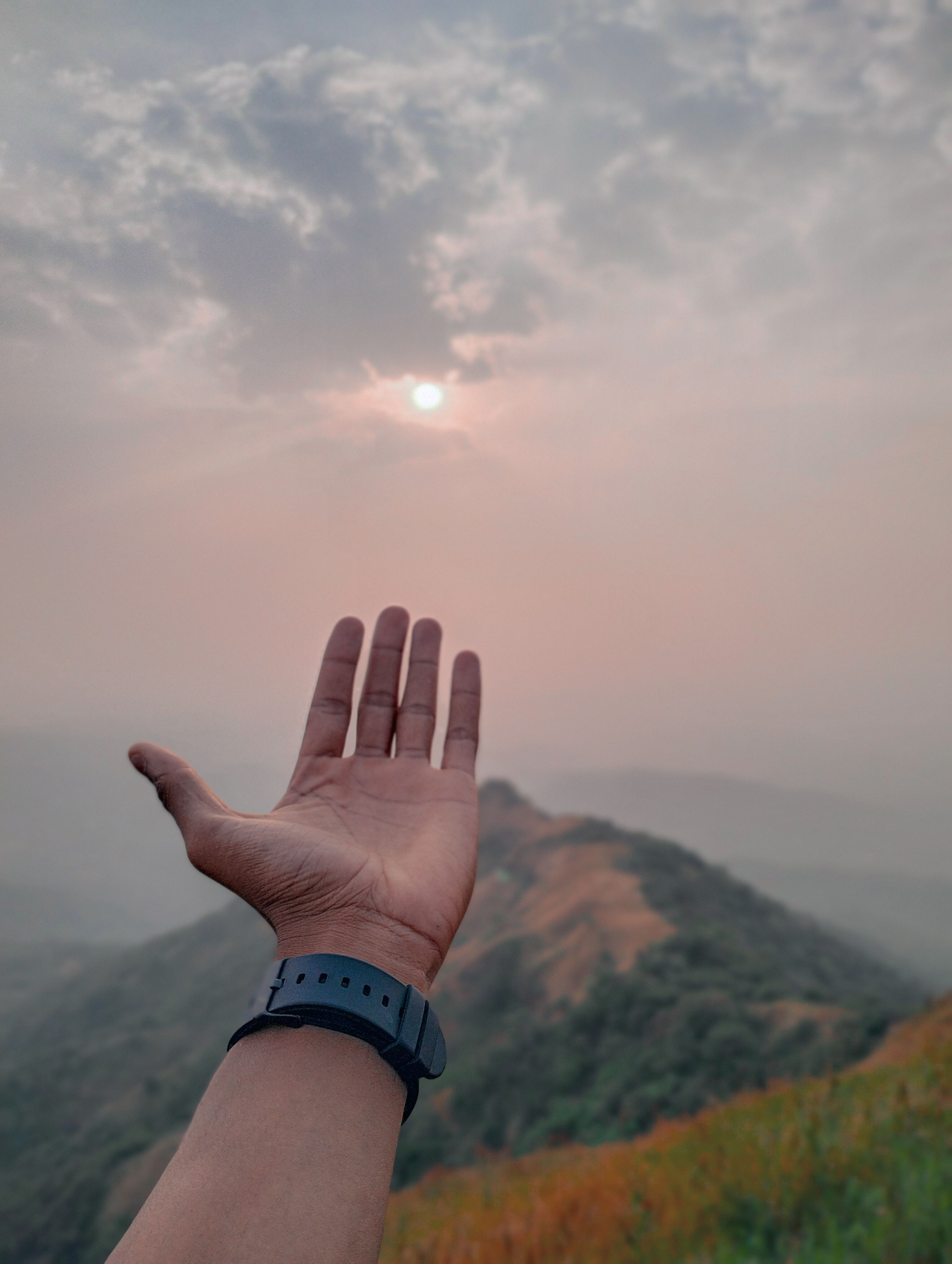 Close-up of a Hand Reaching out and Mountains at Dusk in the Distance ...