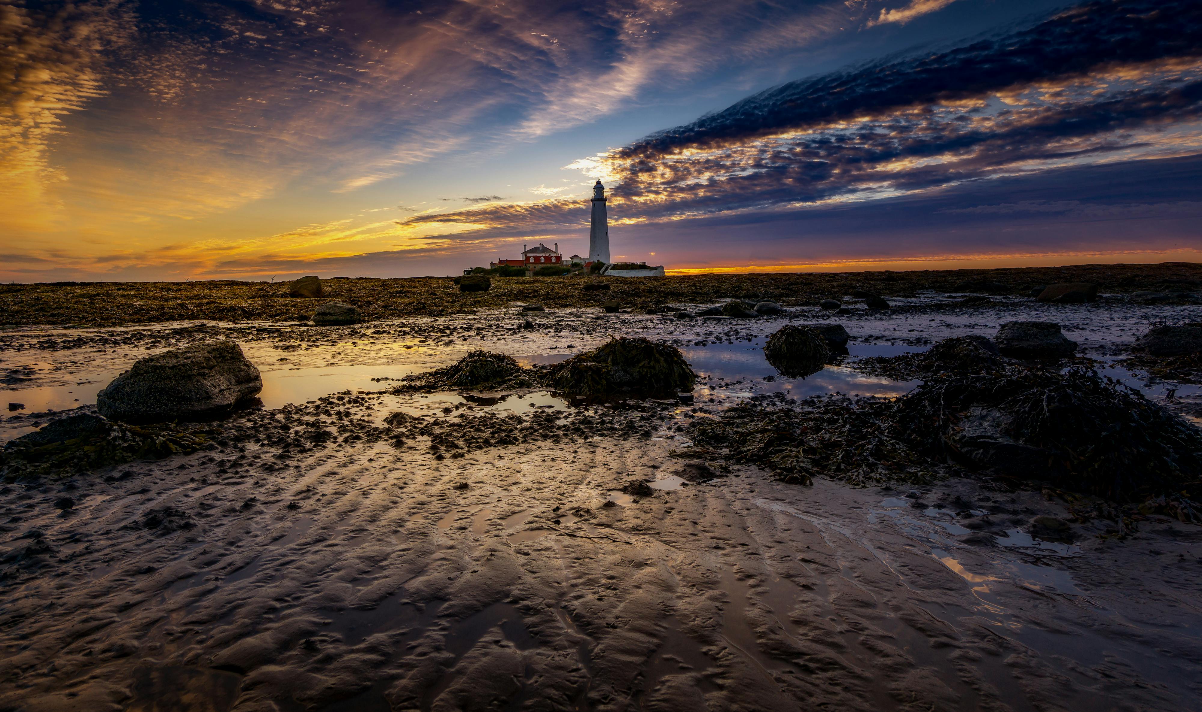 Mud and Rocks on Sea Shore with Lighthouse behind at Sunset · Free ...