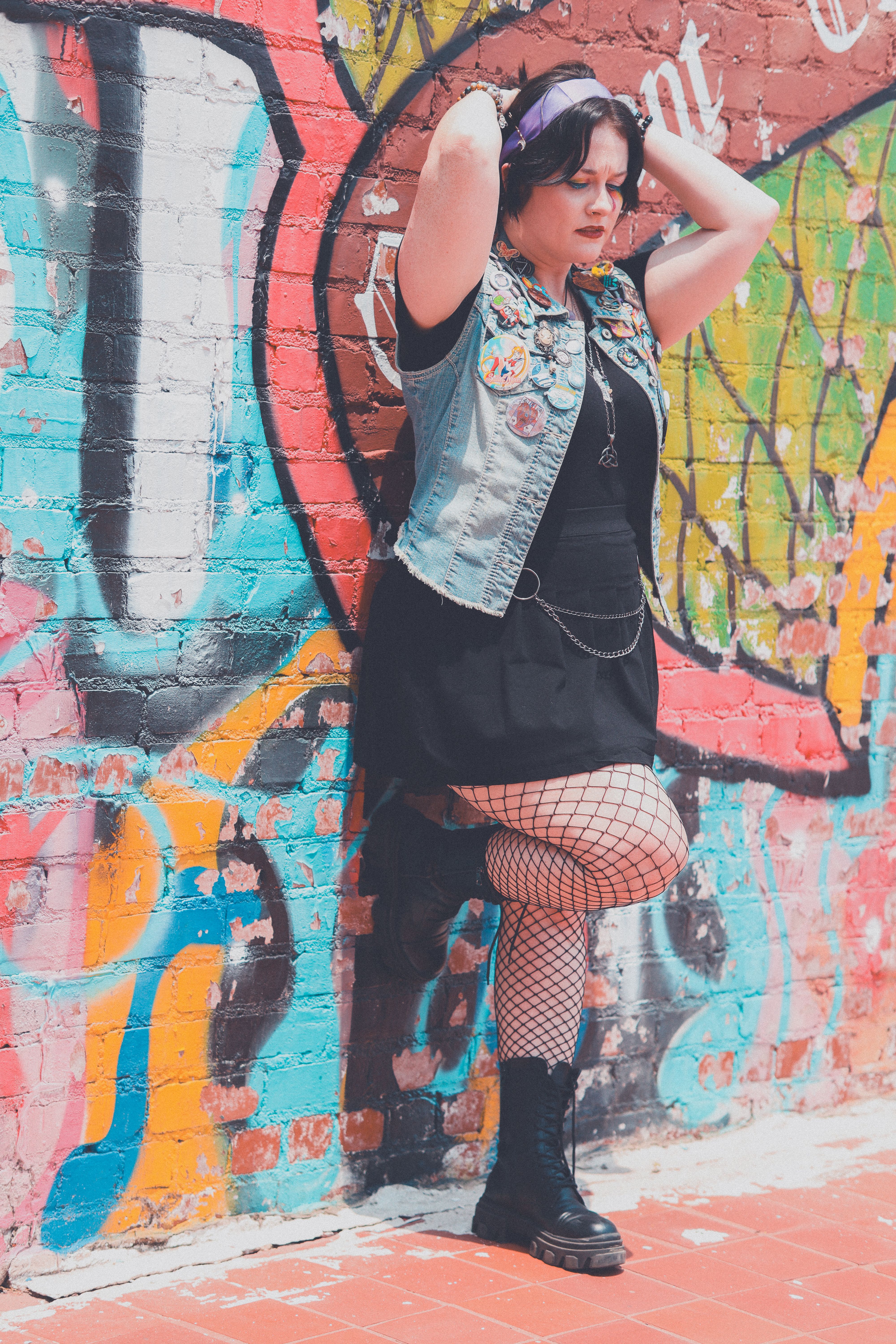 Woman Posing in Blue Denim Vest, Black Mini Dress, and Fishnet Tights ...