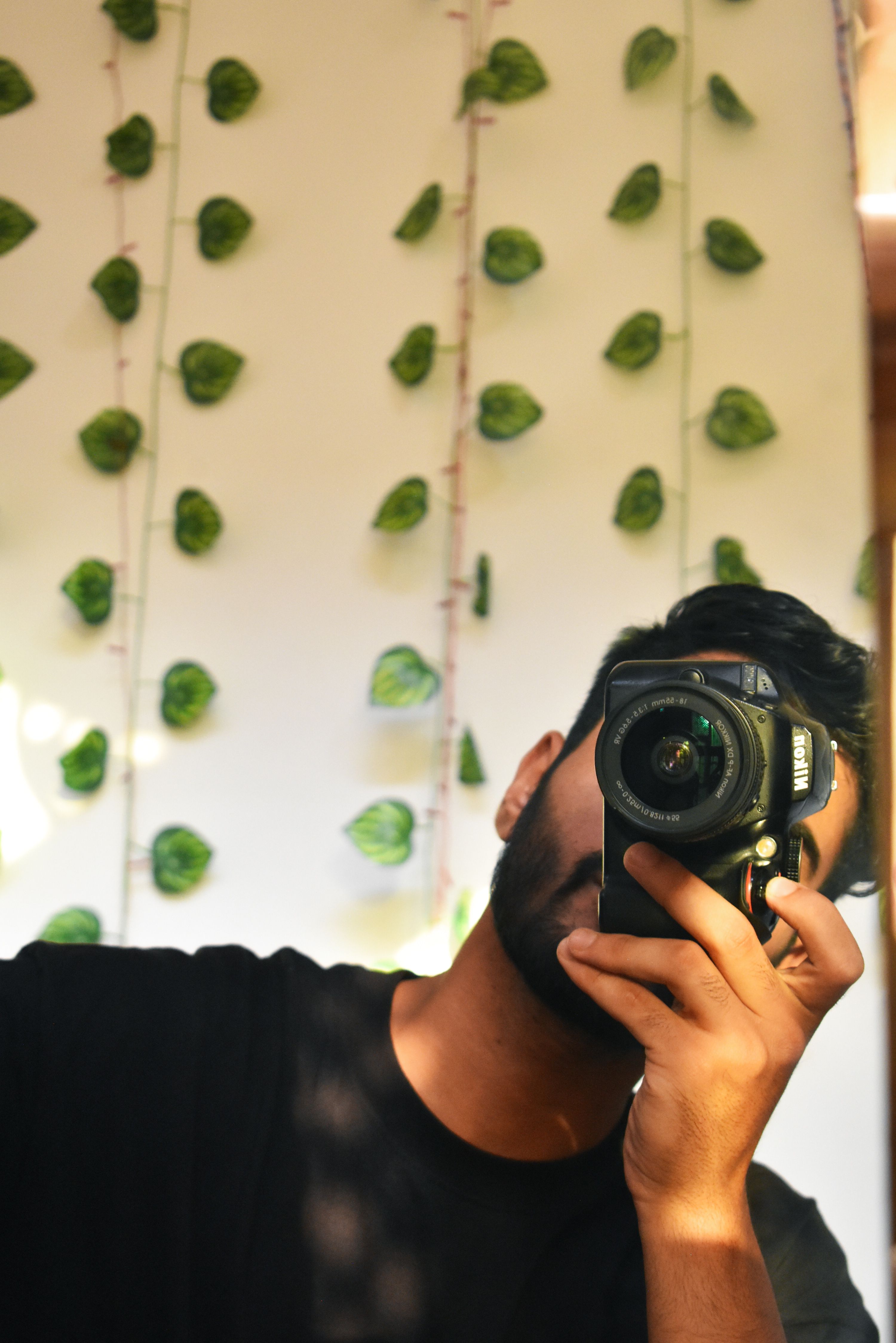 Man Holding a Camera in a Room Decorated with Leaves · Free Stock Photo
