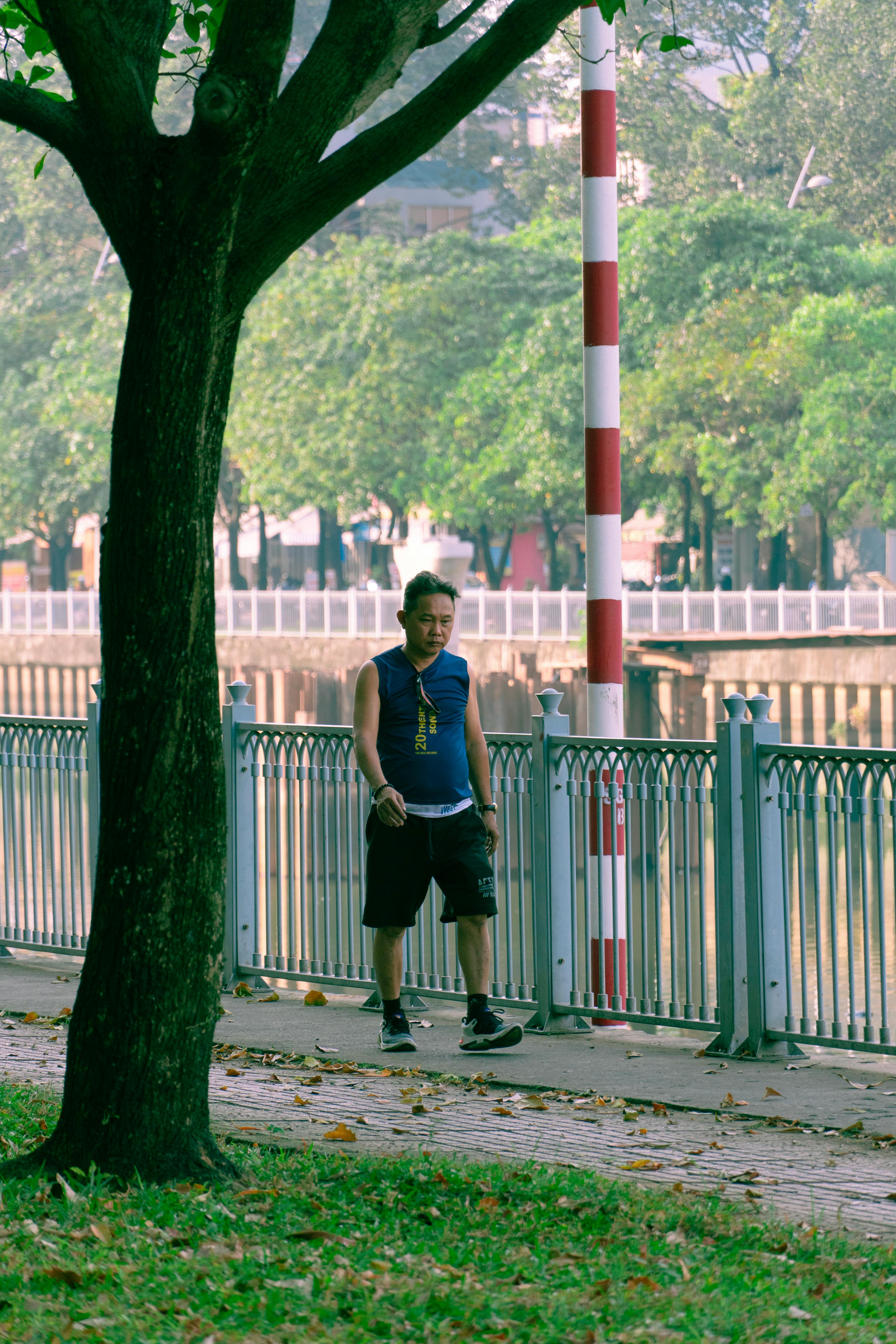 Man Walking near Tree and Railing · Free Stock Photo