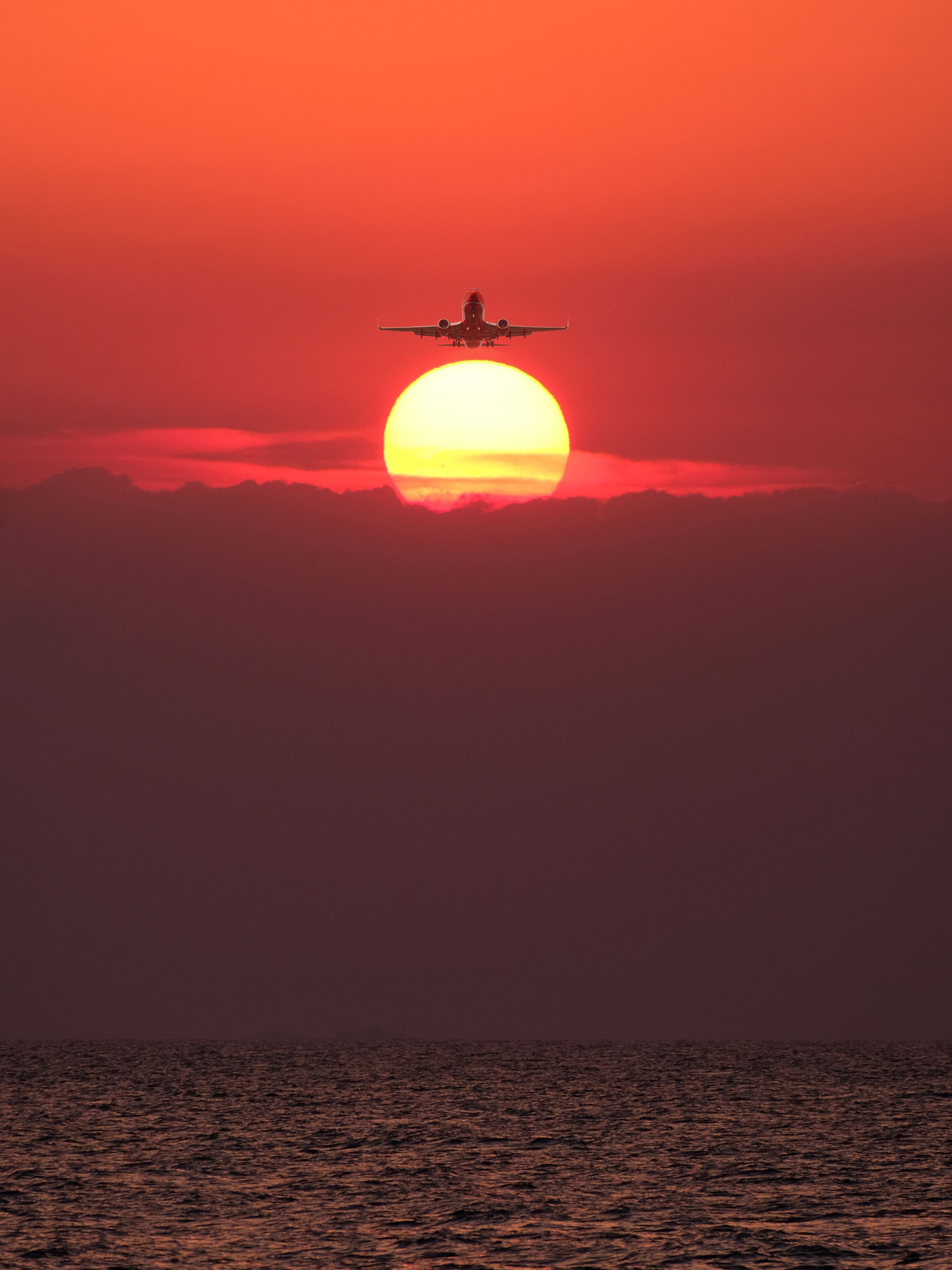 Airplane over Sun on Red Sky over Sea at Sunset · Free Stock Photo