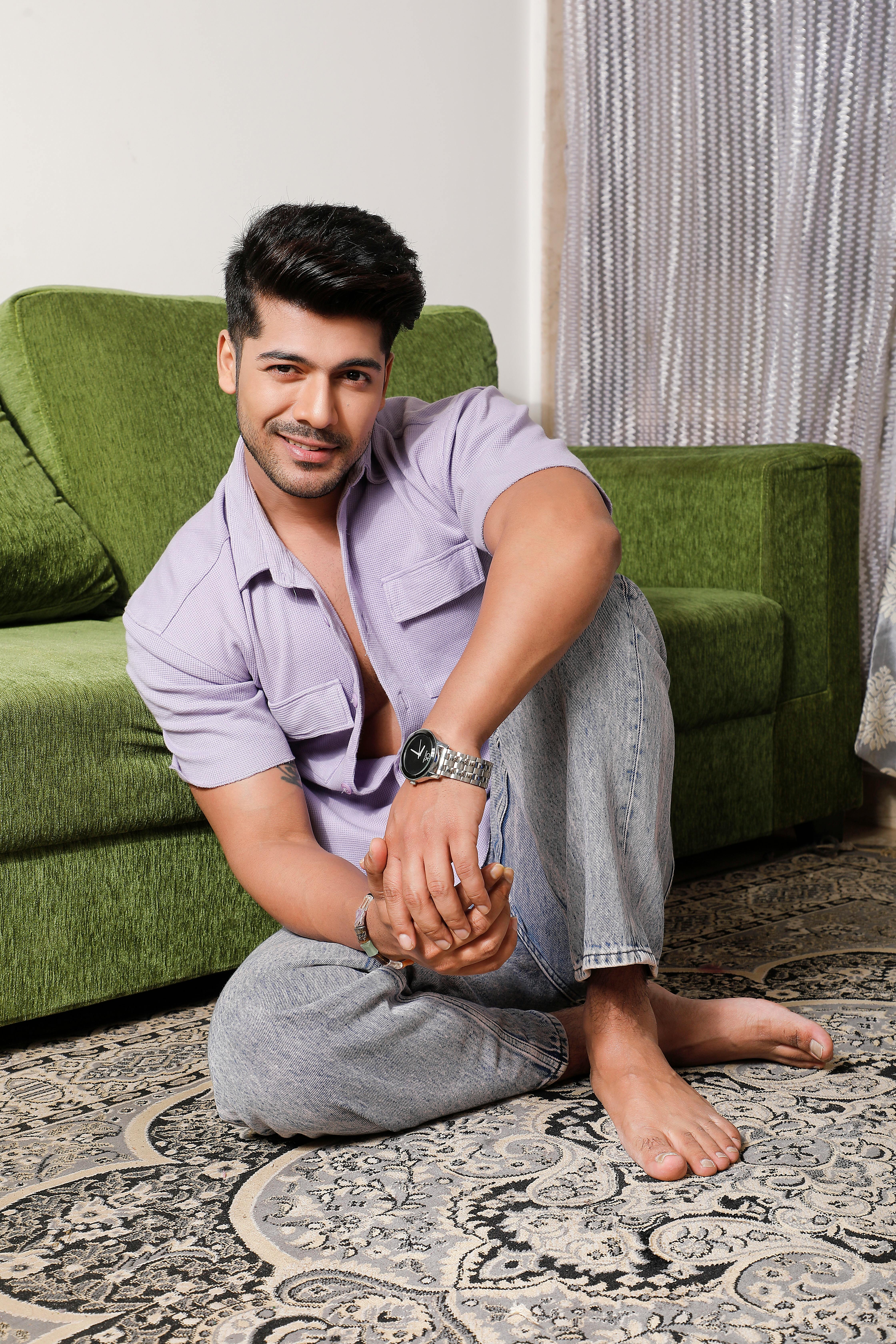 Young Man in Jeans and Shirt Sitting on the Rug by the Sofa at Home ...