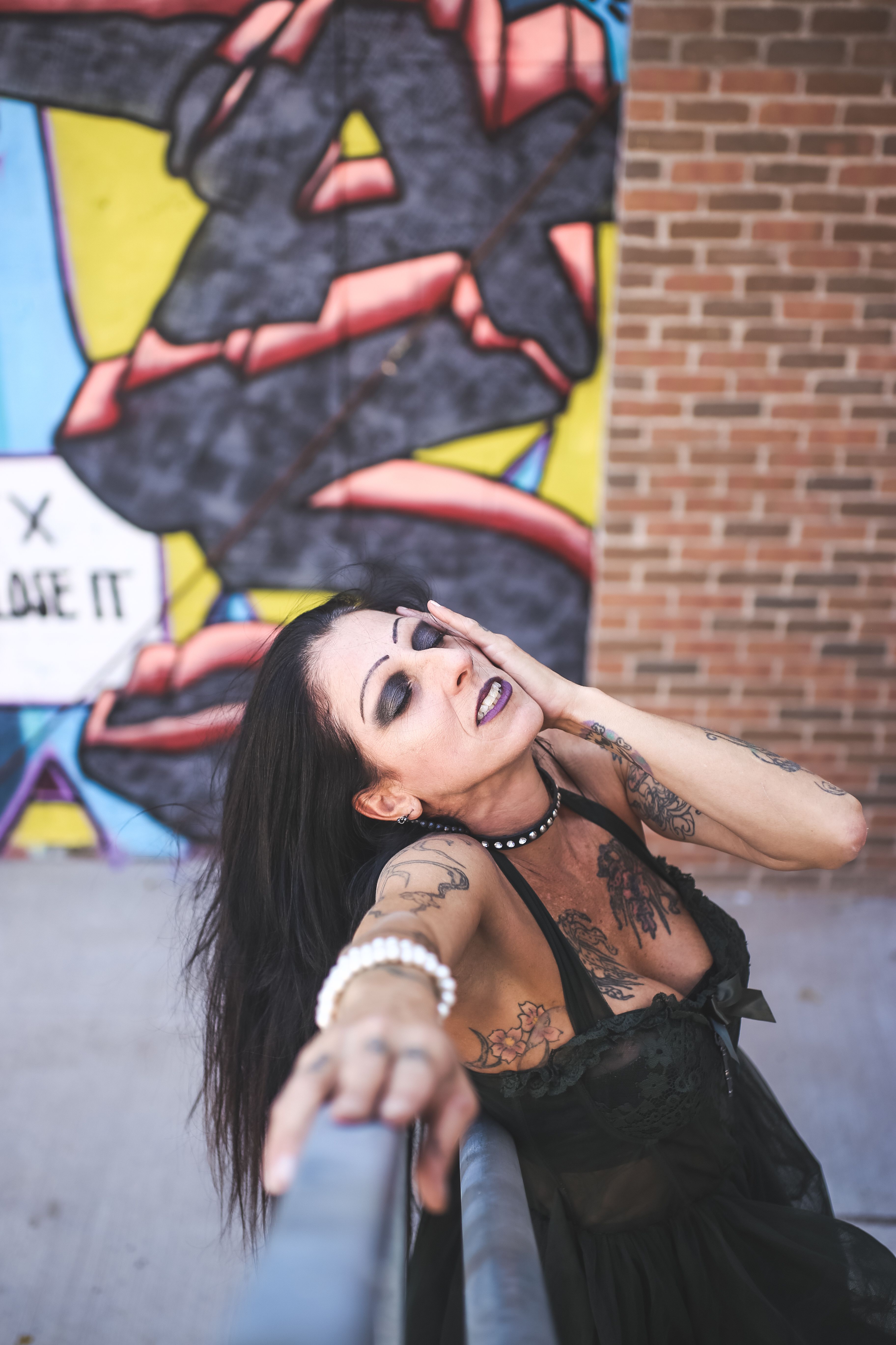 Beautiful Tattooed Woman In Black Dress Posing By Railing · Free Stock