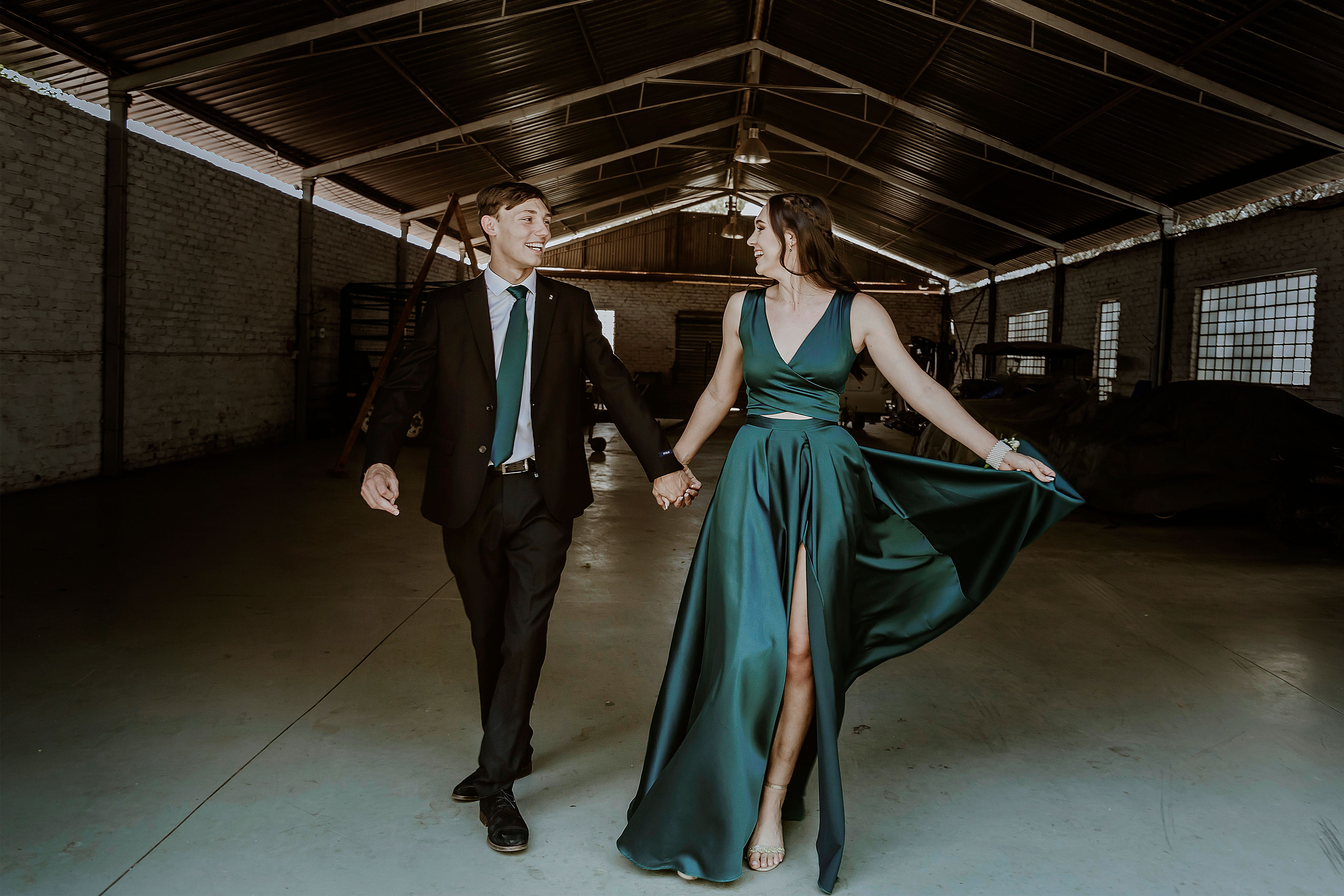 Elegant Couple Walking Hand in Hand in a Hangar · Free Stock Photo