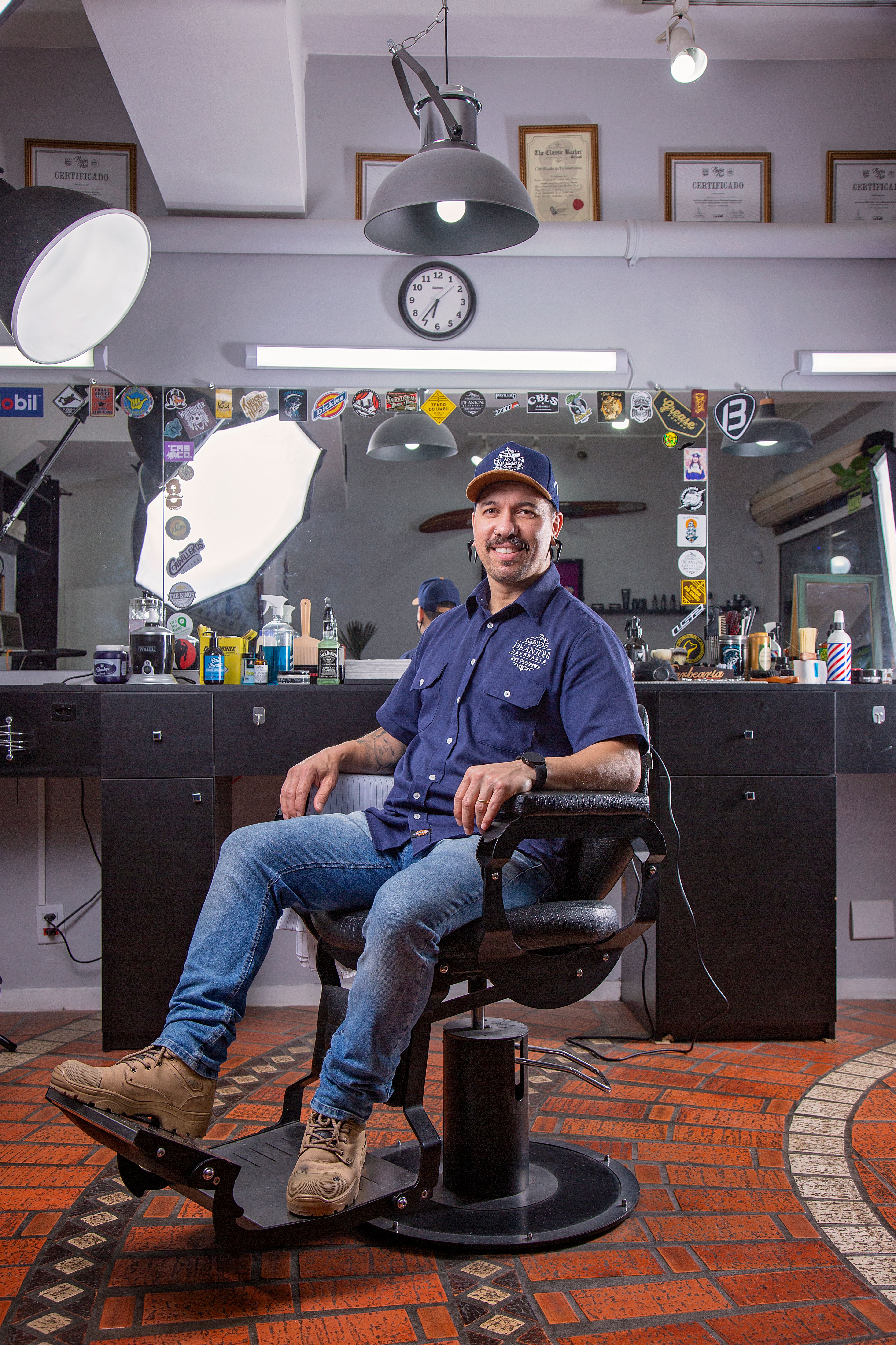Smiling Barber Sitting on Armchair in Hair Salon · Free Stock Photo