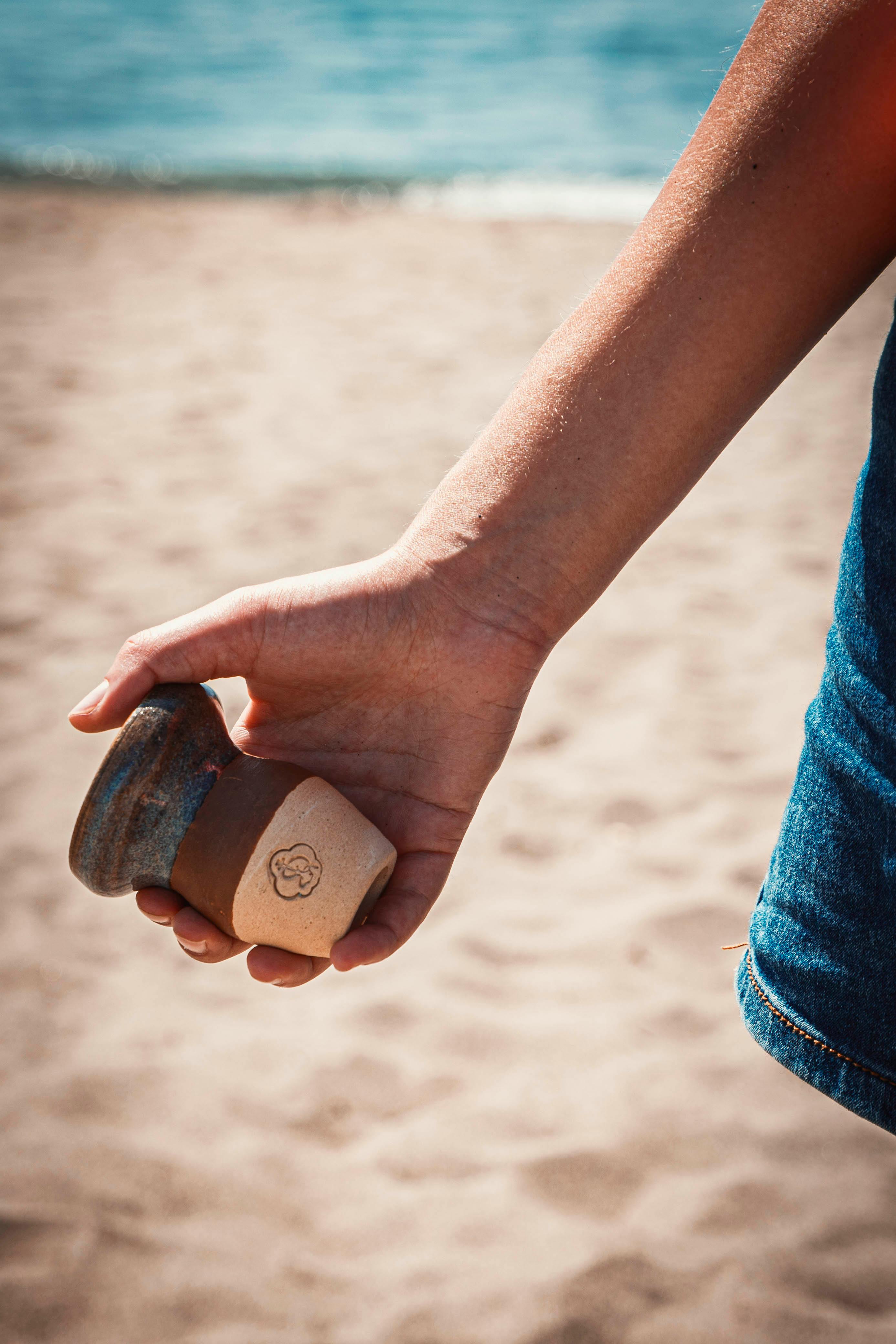 Hand Holding Item on Beach · Free Stock Photo