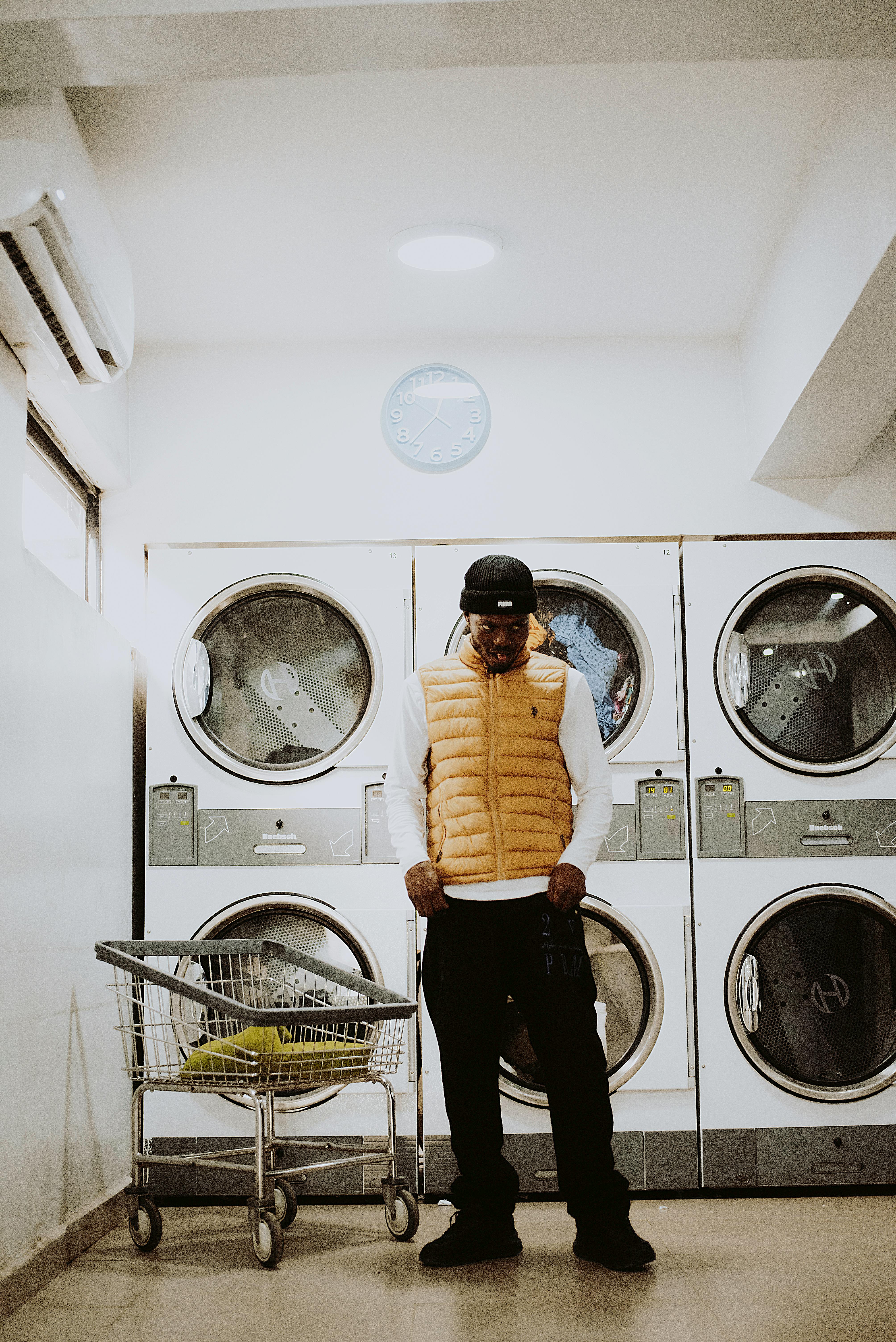 Man in Puffer Vest and Hat Posing in Laundry Room · Free Stock Photo