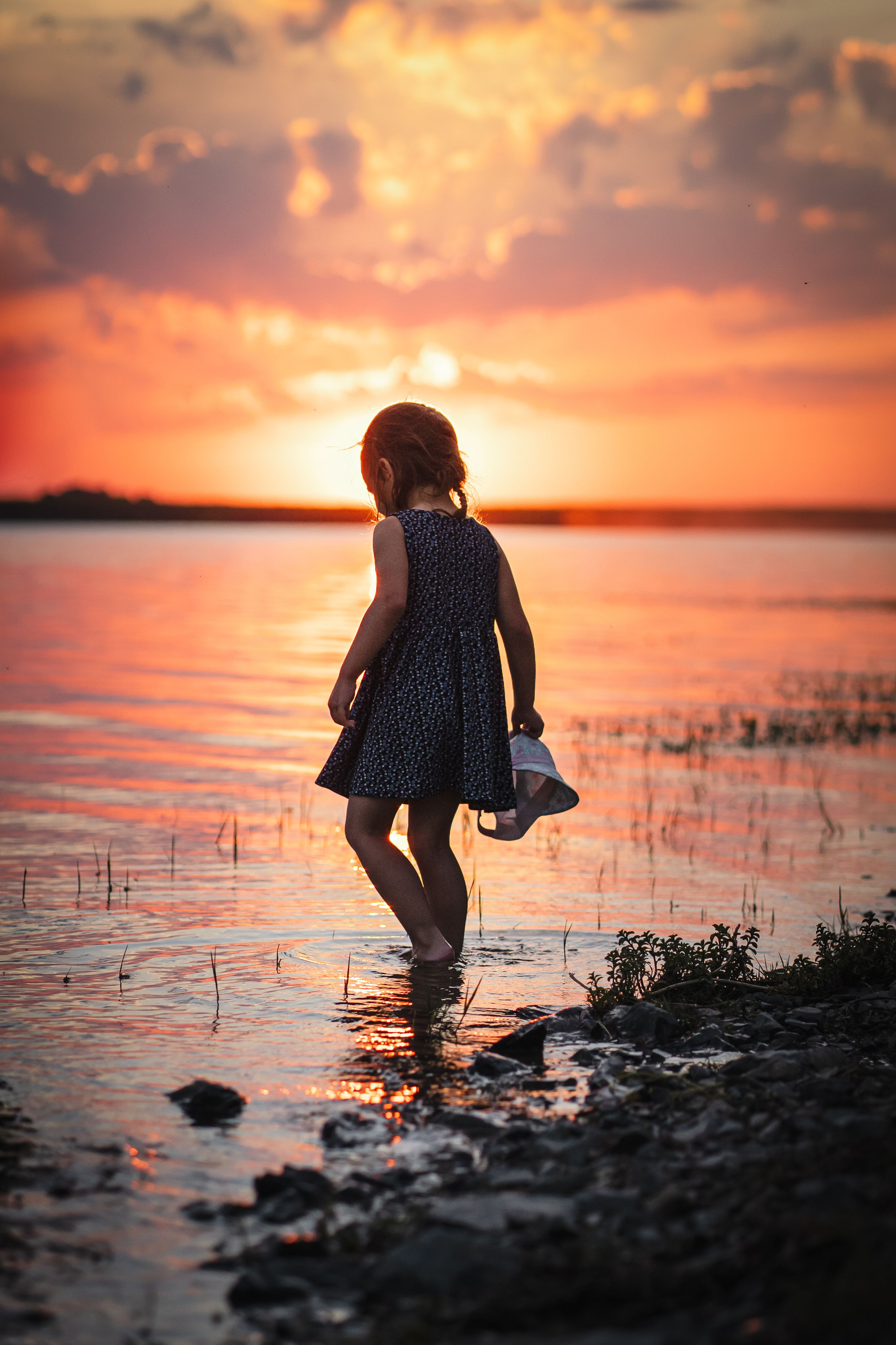 A Little Girl Walking Ankles Deep in Water at Sunset · Free Stock Photo