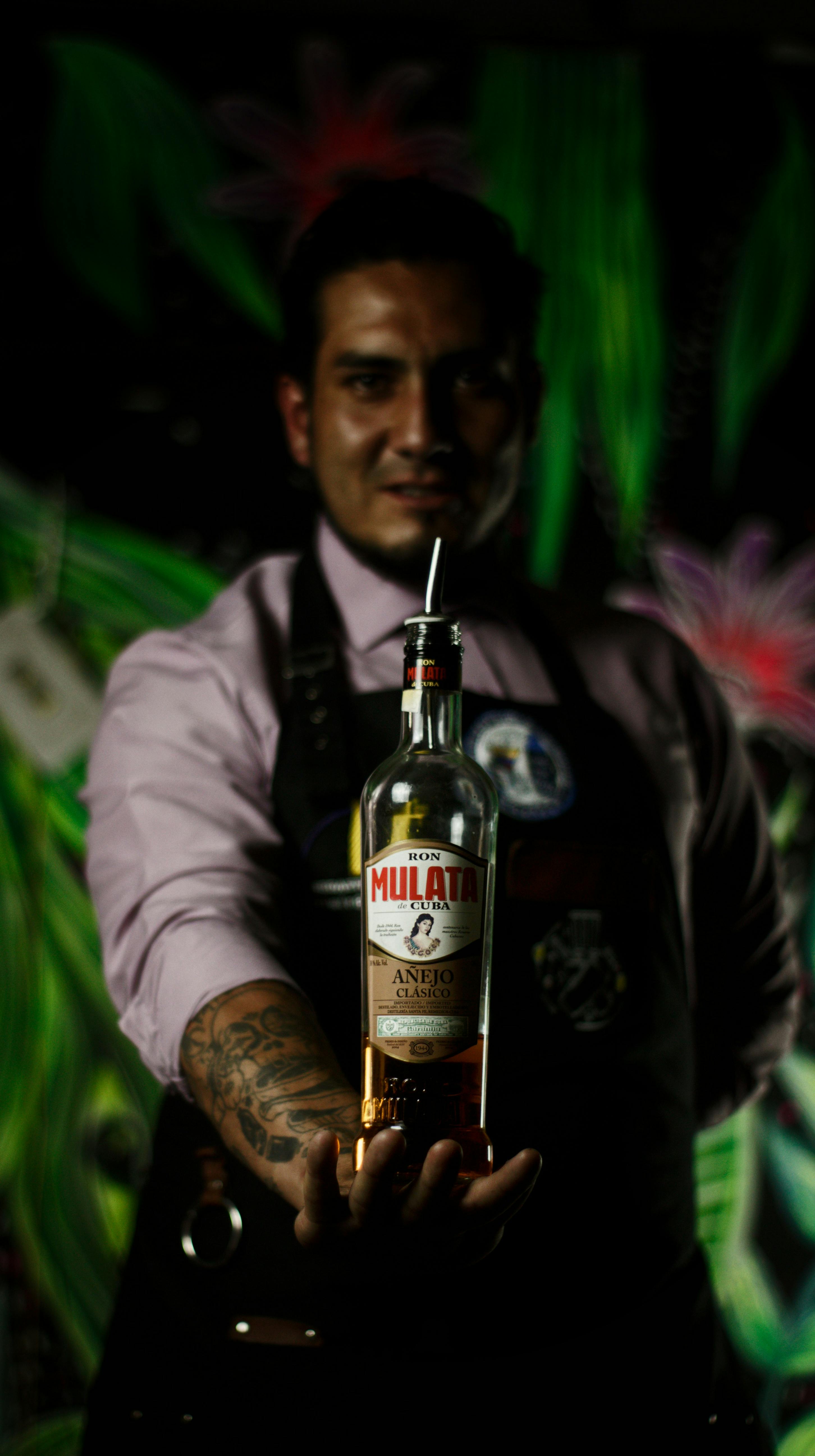 A Waiter Serving a Bottle of Cuban Alcohol · Free Stock Photo