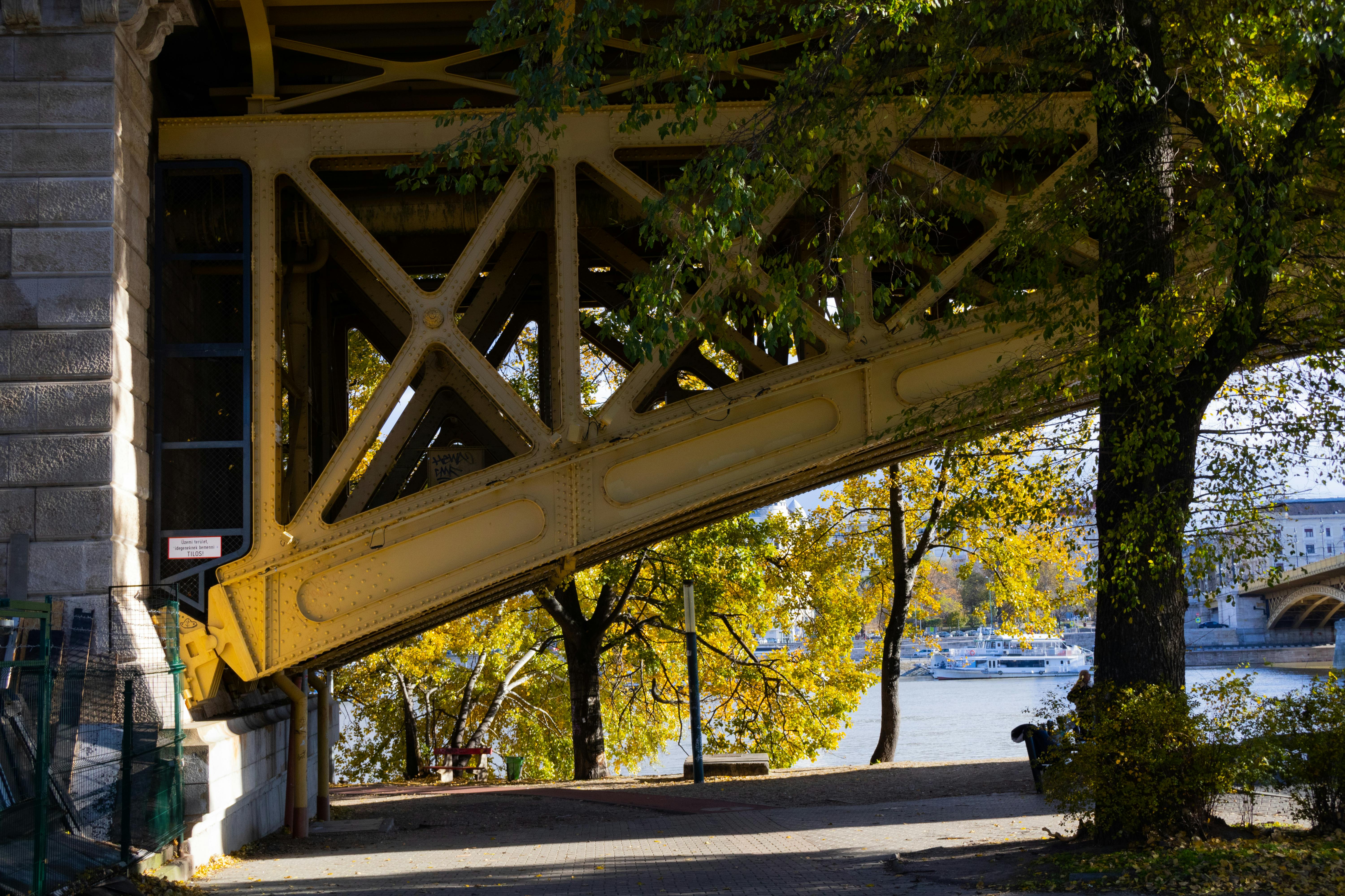 A yellow bridge over a body of water with trees · Free Stock Photo
