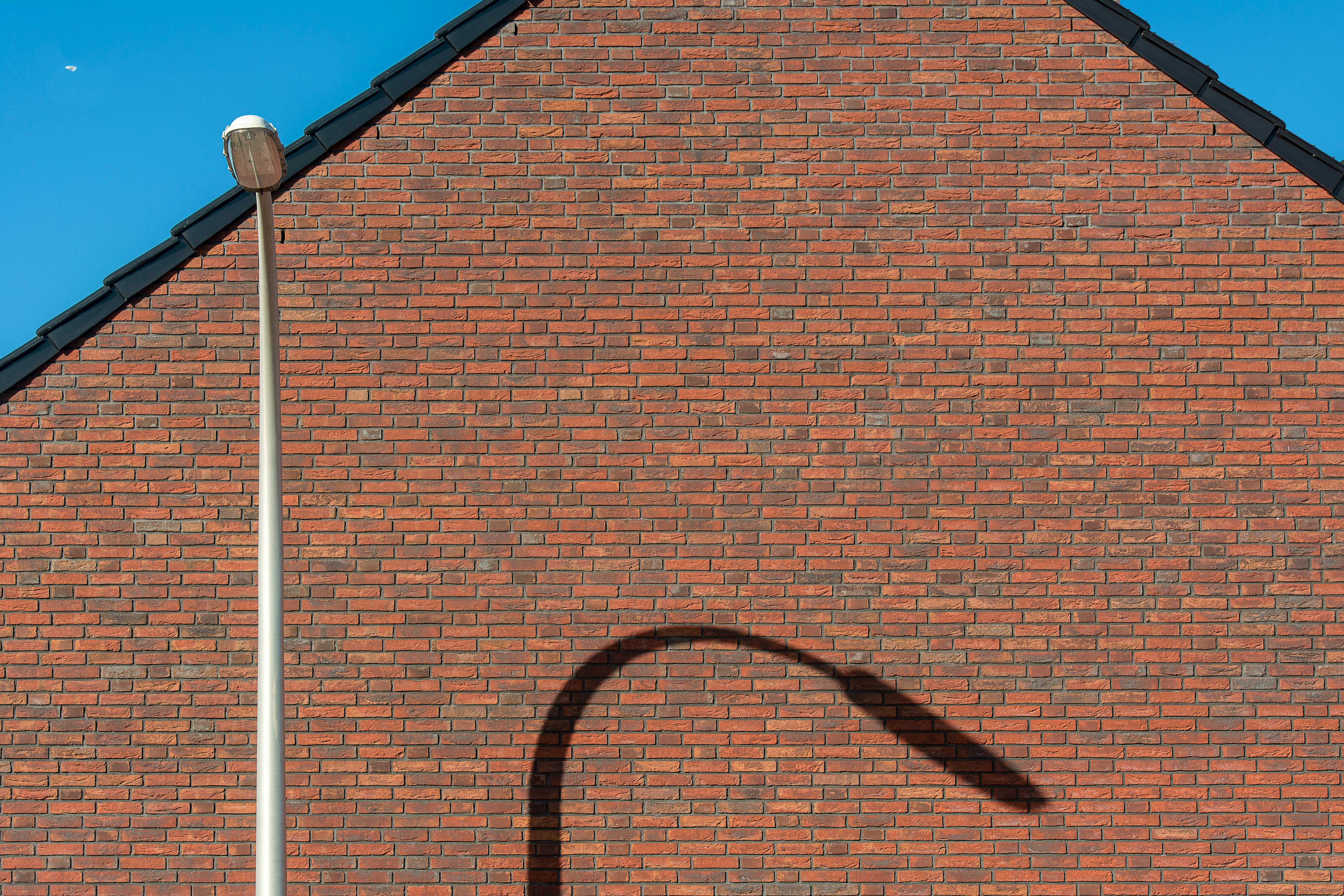 Streetlight Casting Shadow on Red Brick Wall · Free Stock Photo